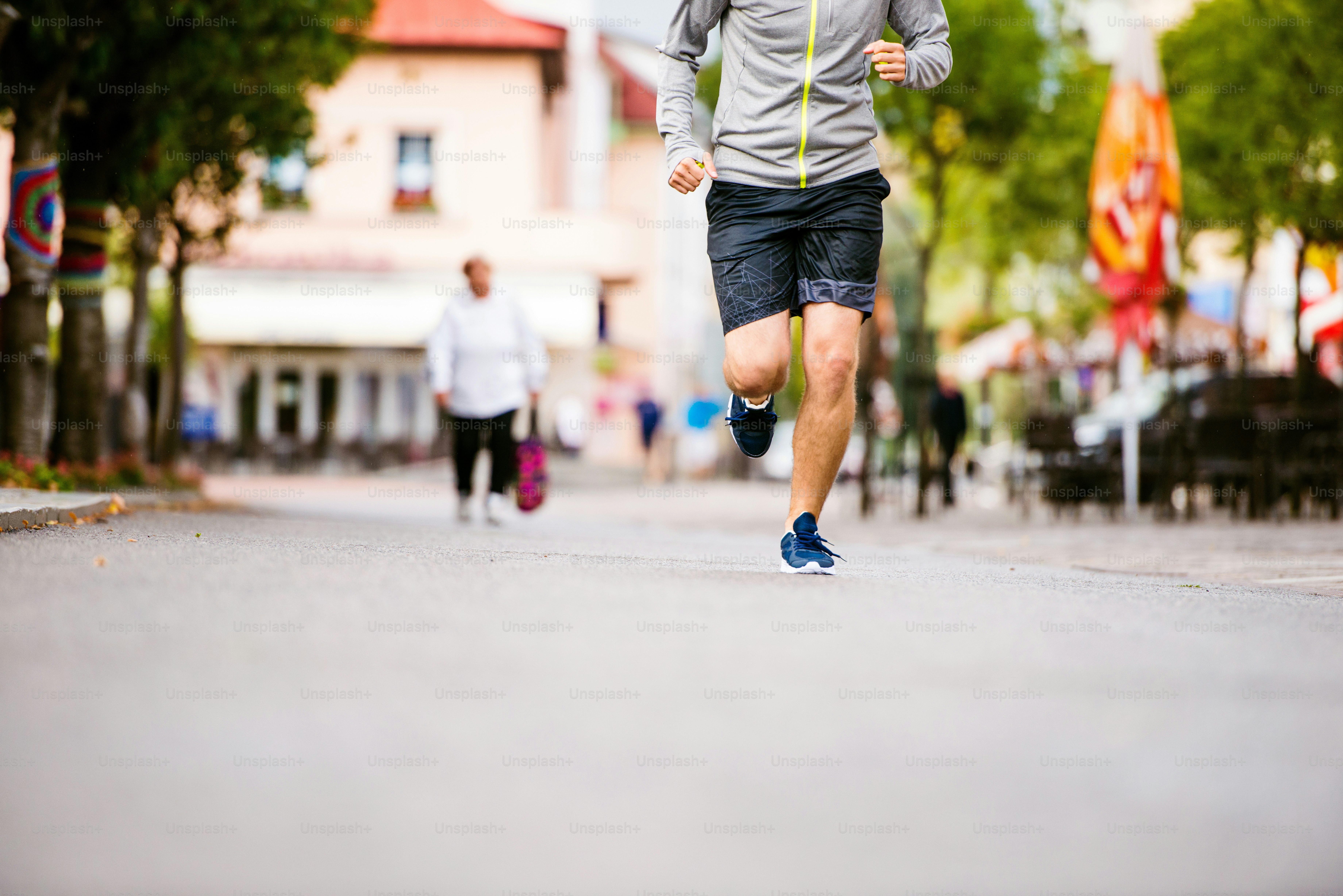 Unrecognizable young man in gray sweatshirt running in town, main ...