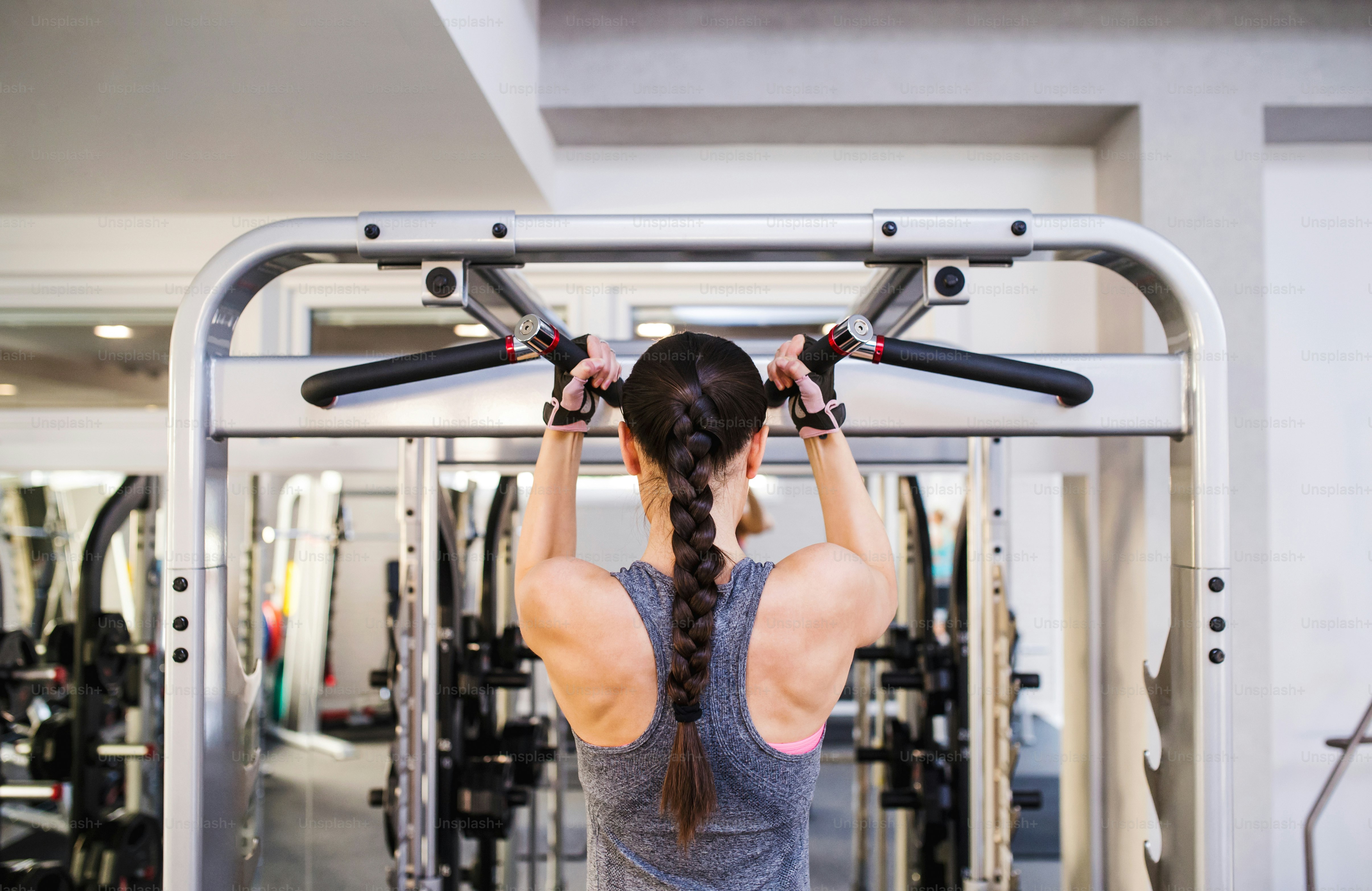 Close up of attractive fit woman flexing back muscles on cable machine ...