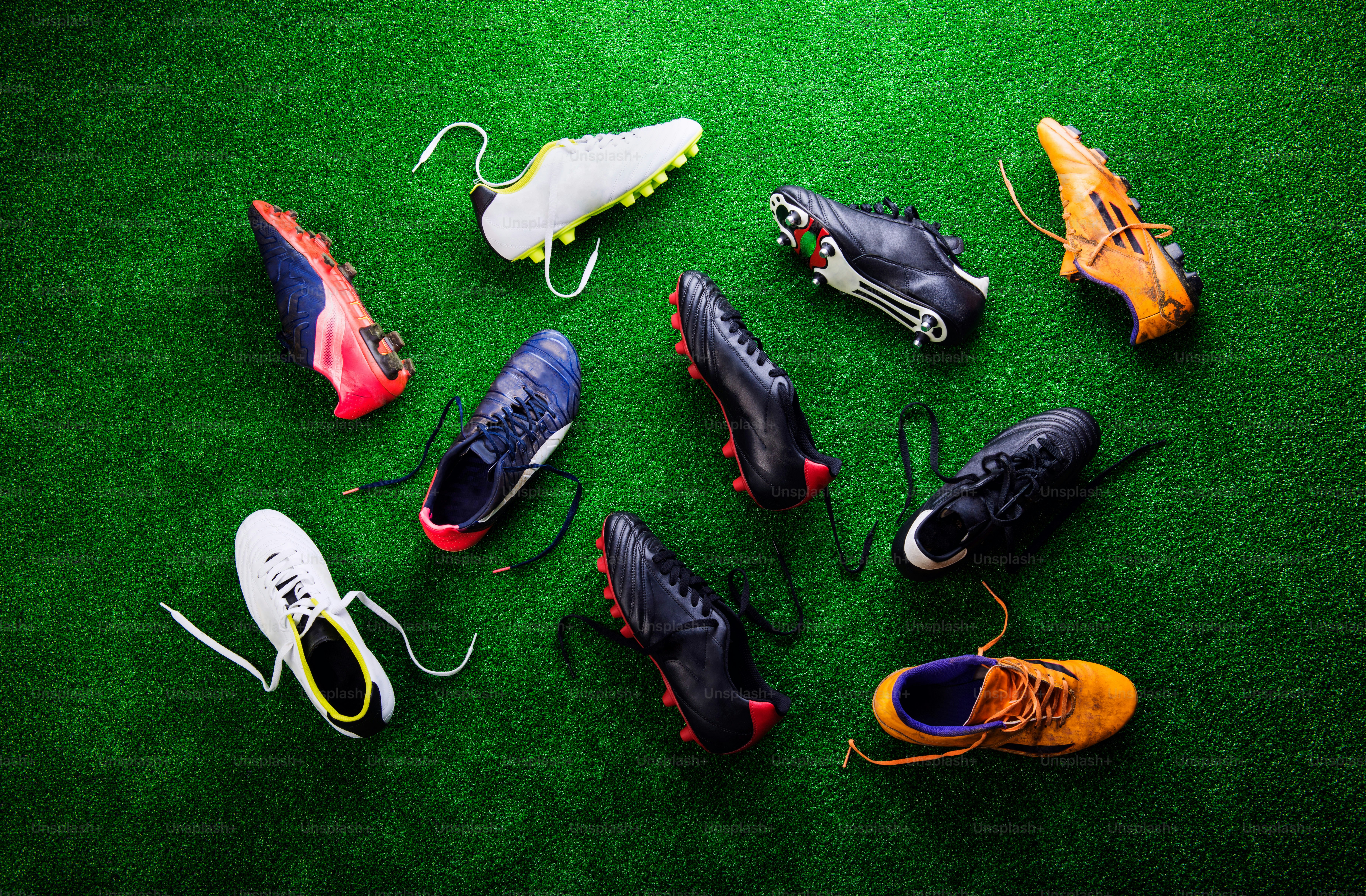 Various colorful cleats against artificial turf, studio shot on green ...