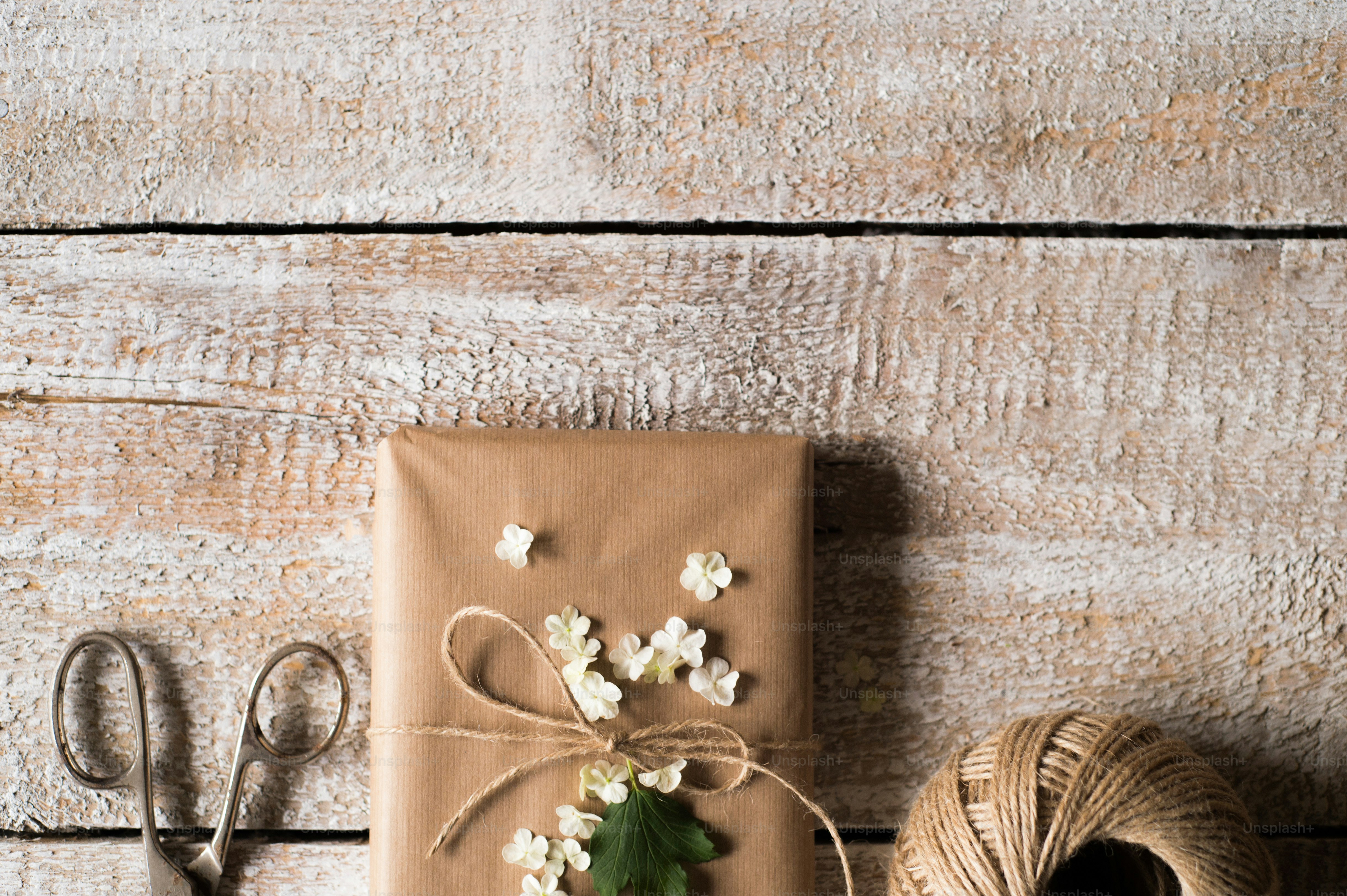 Present wrapped in brown paper decorated by lilac flower. Scissors and ...