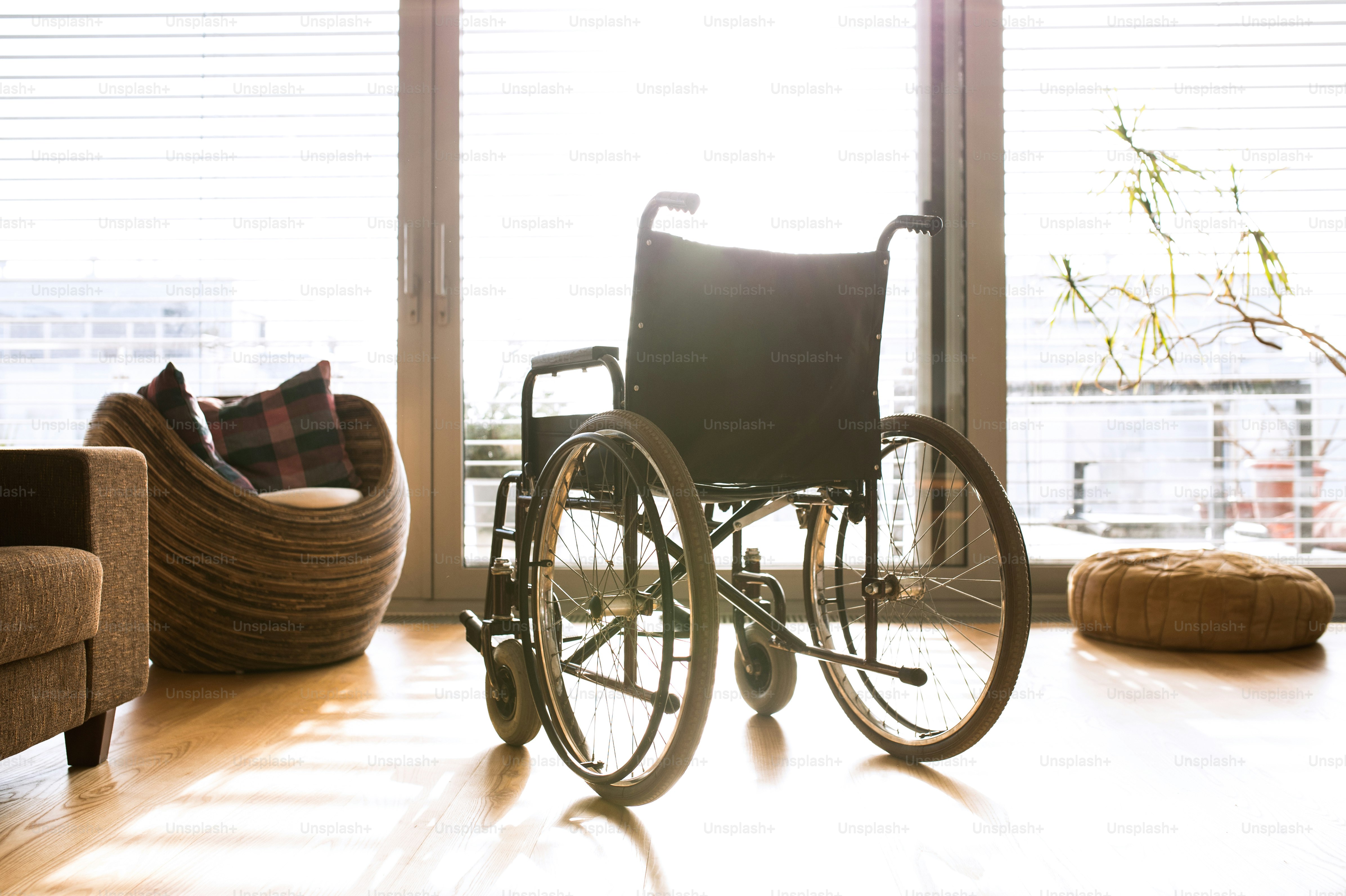 Empty wheelchair in sunny living room next to the couch photo – Medical ...