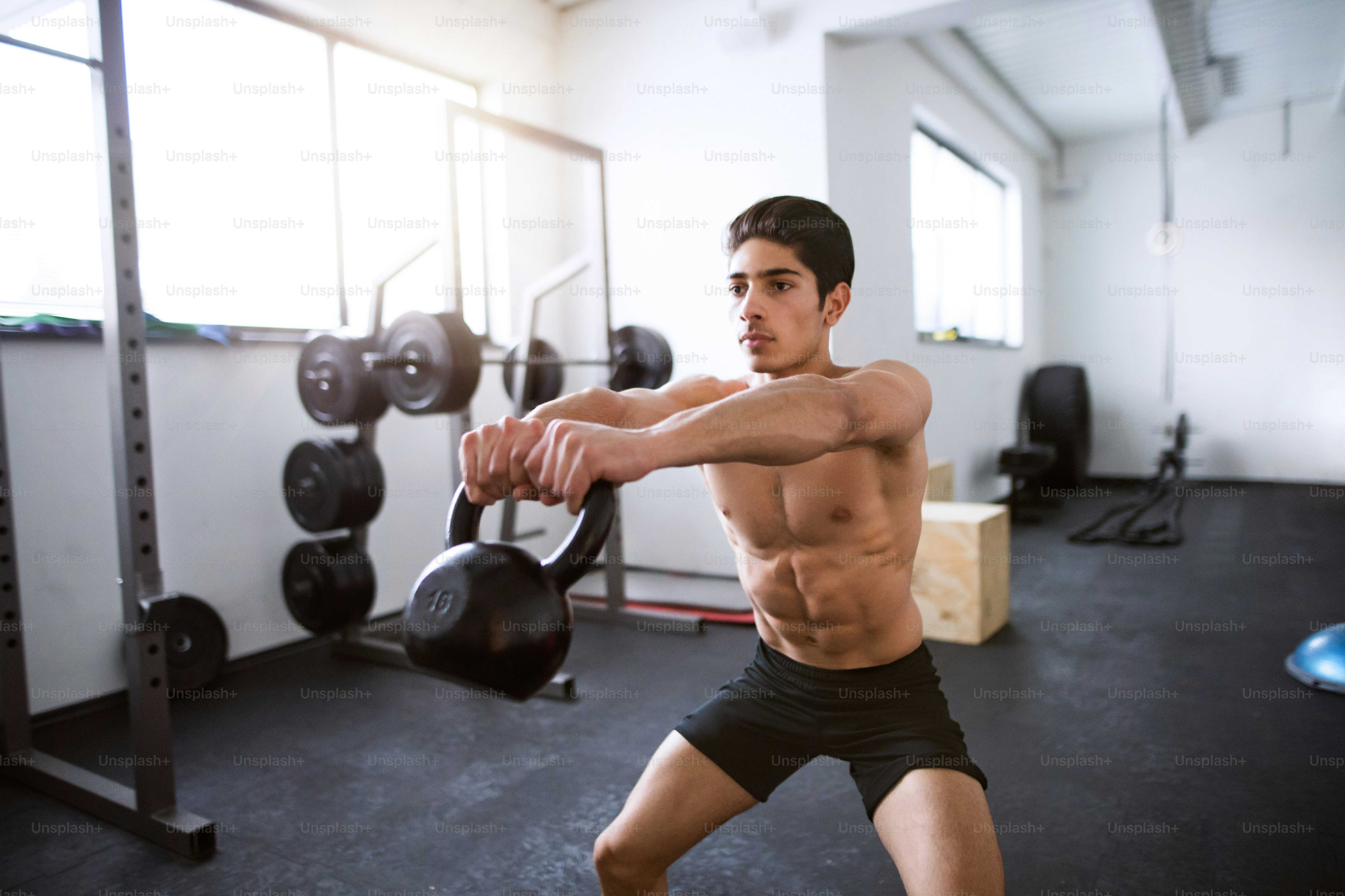 Fit hispanic man doing strength training, doing kettlebell swings in ...