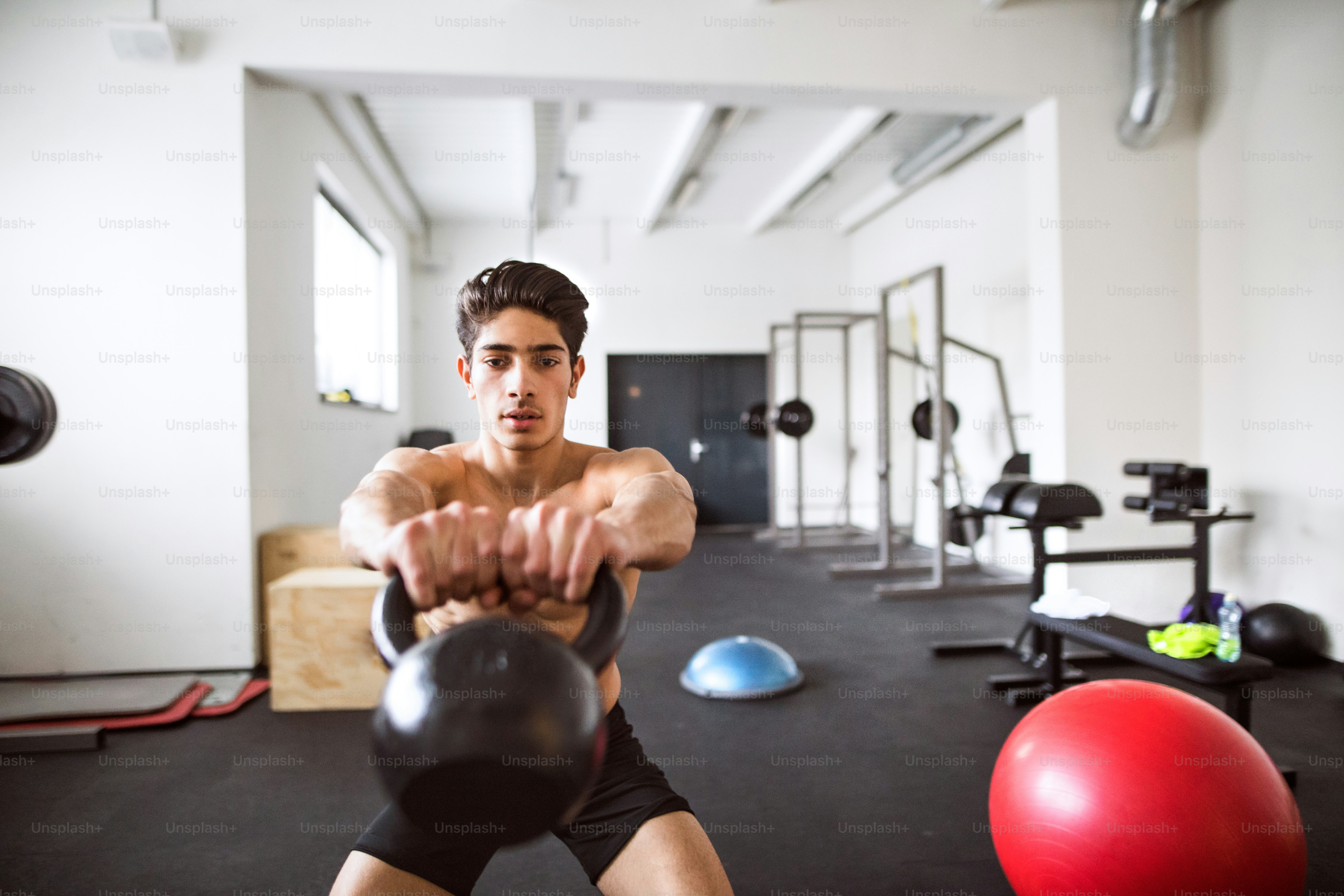 Fit hispanic man doing strength training, doing kettlebell swings in gym gym photo – Muscle ...