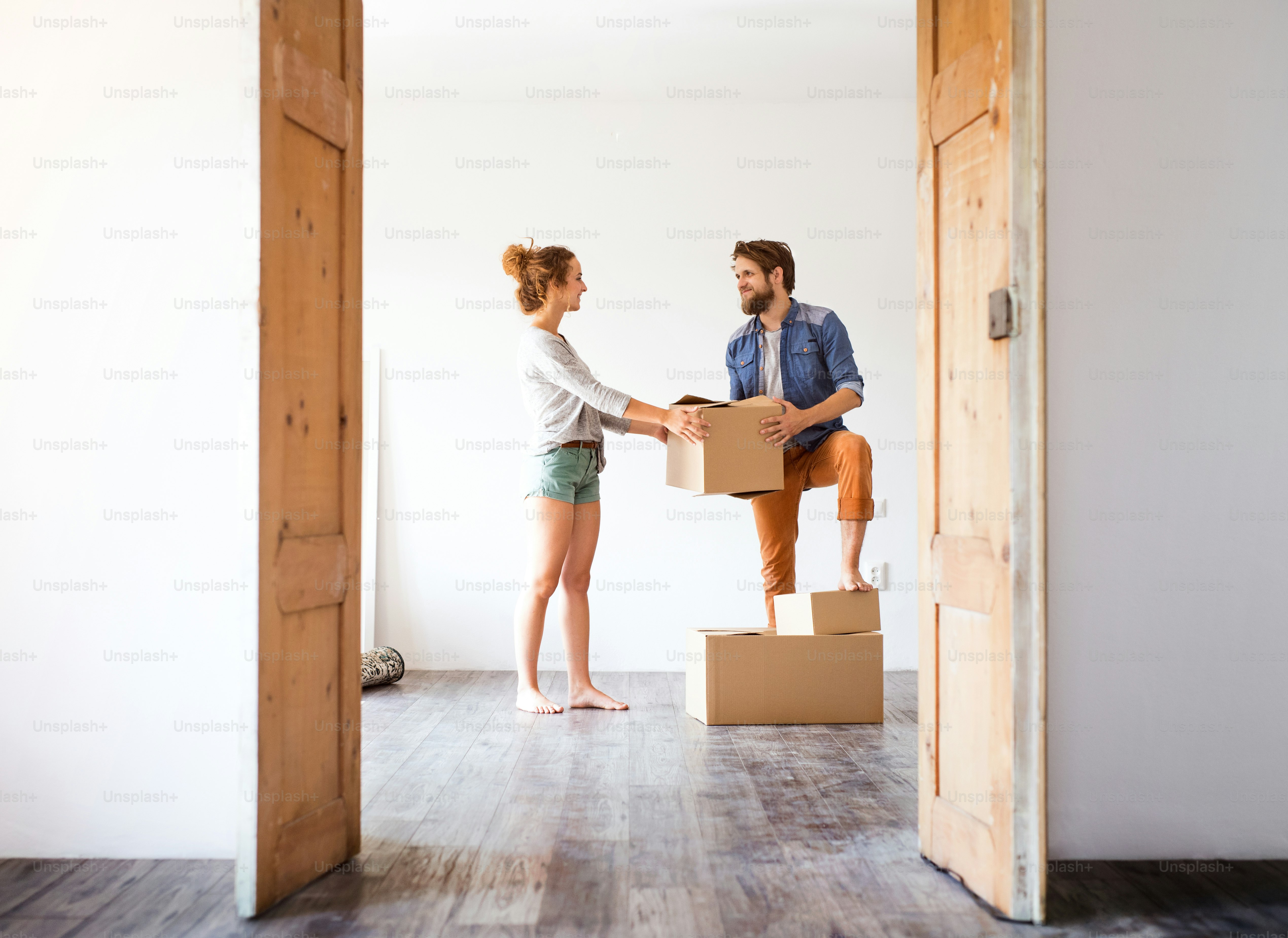 Young married couple moving in new house, holding big cardboard boxes ...