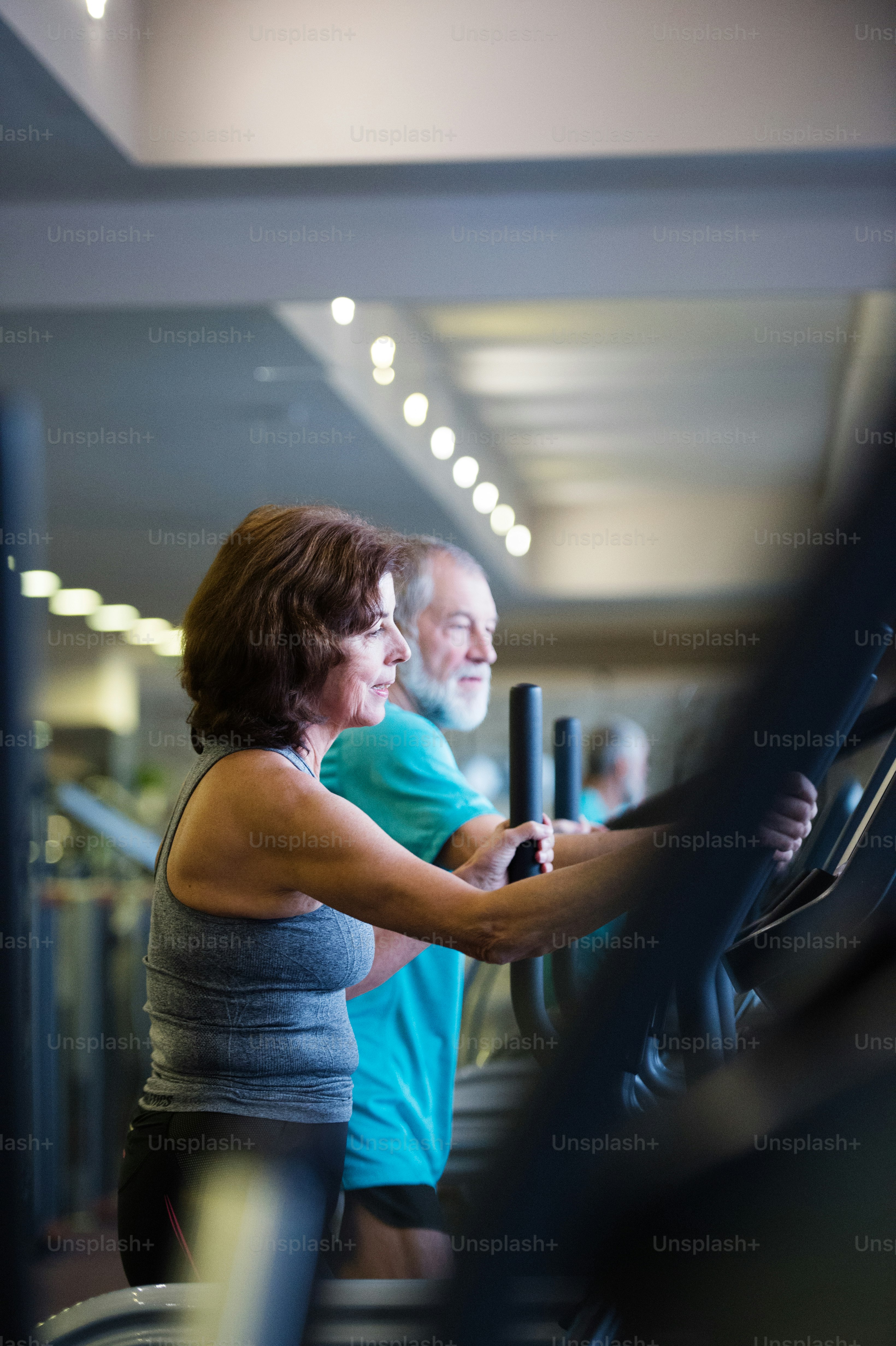 Beautiful fit senior couple in sports clothing in gym doing cardio ...