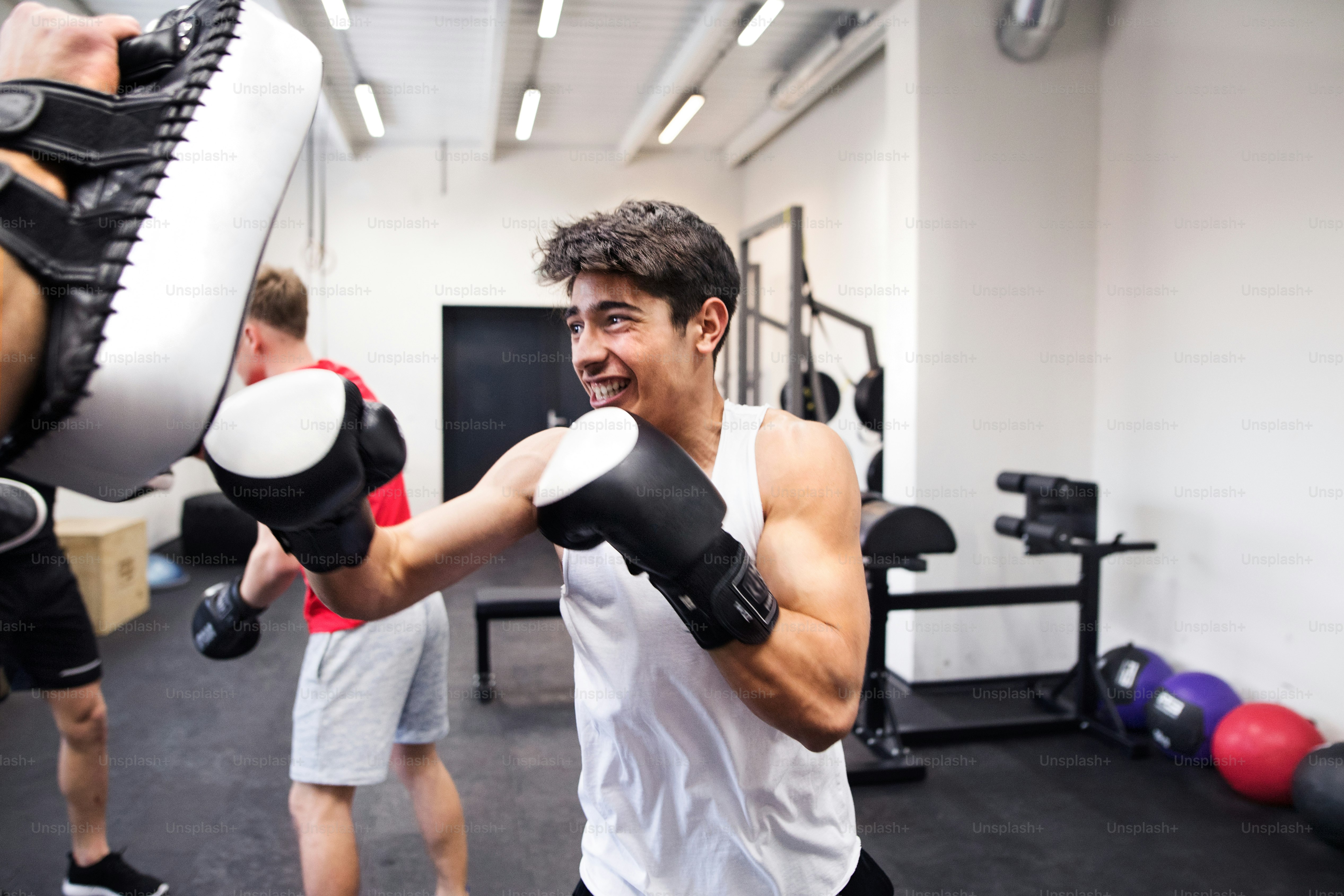 Foto Guapo hombre hispano en forma en el gimnasio de boxeo con su irreconocible entrenador ...