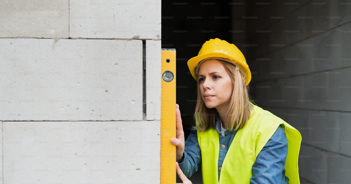 建設現場の女性作業員。ビルディングブロックを測定する美しい若い女性。住宅建設。の写真 衣類 Unsplashの写真