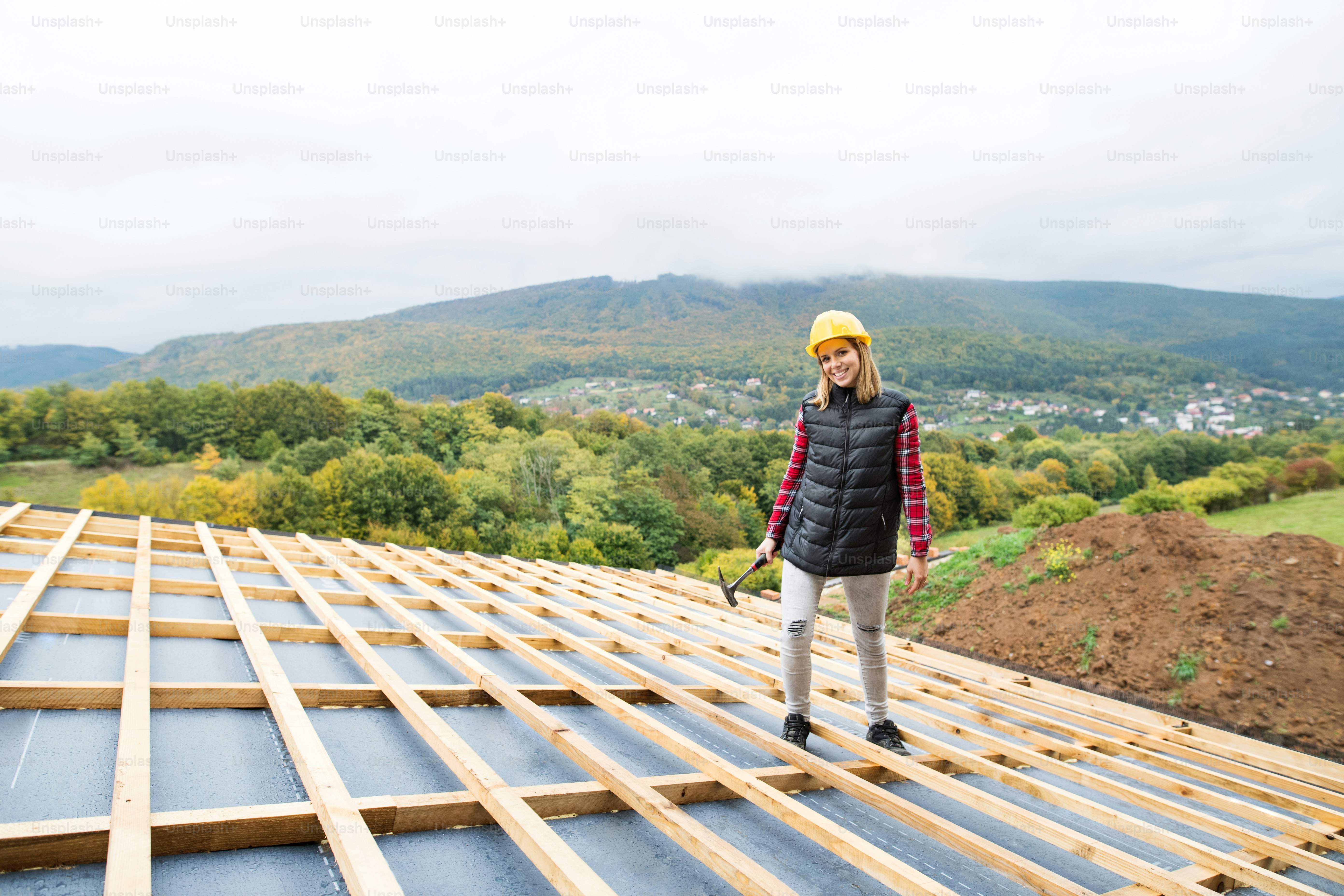 Female worker on the building site. Young woman working as a roofer ...