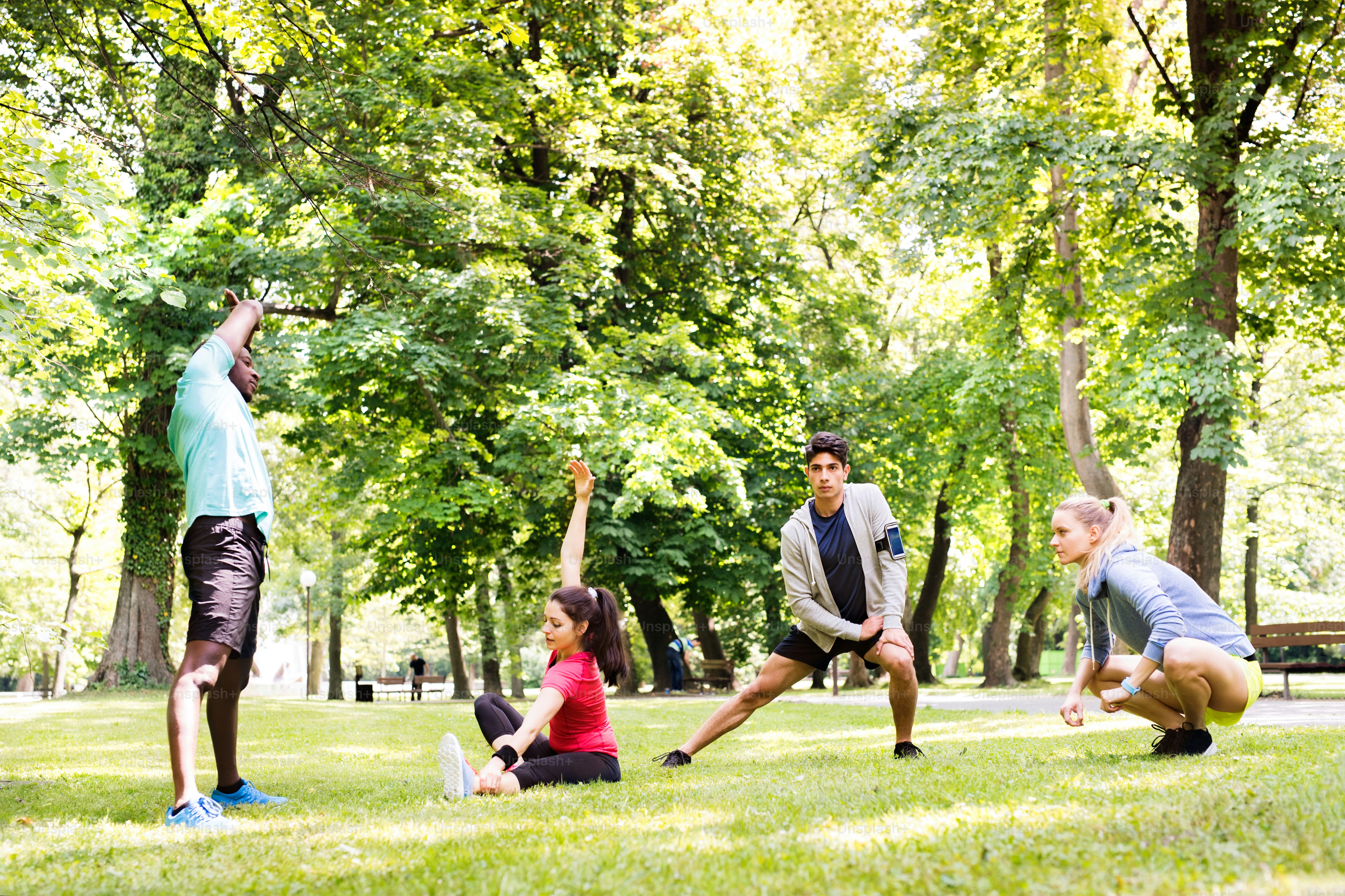 Foto Grupo de jóvenes corredores en la naturaleza calentando y ...