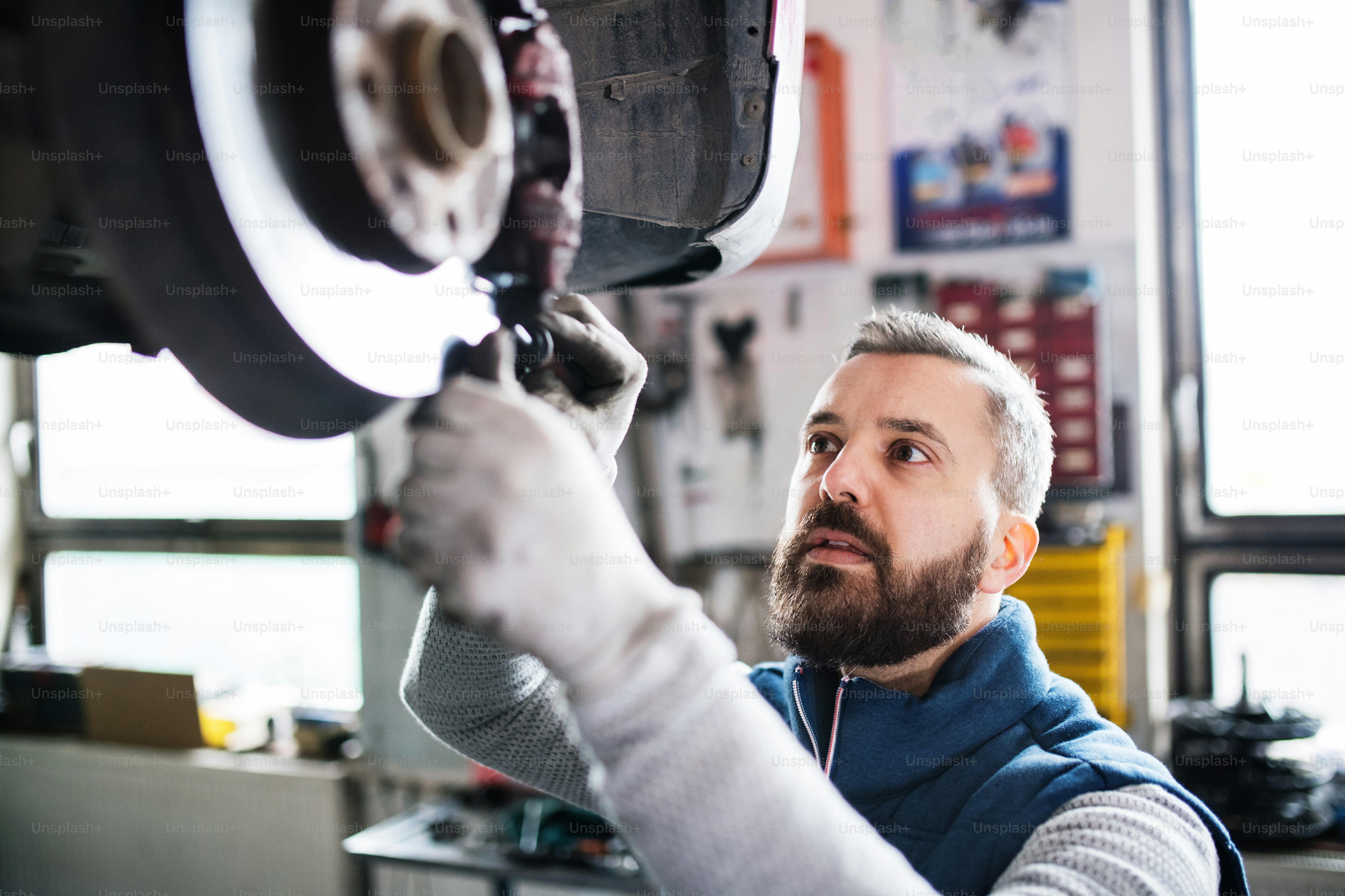 Mature man mechanic repairing a car in a garage. photo – Store Image on ...