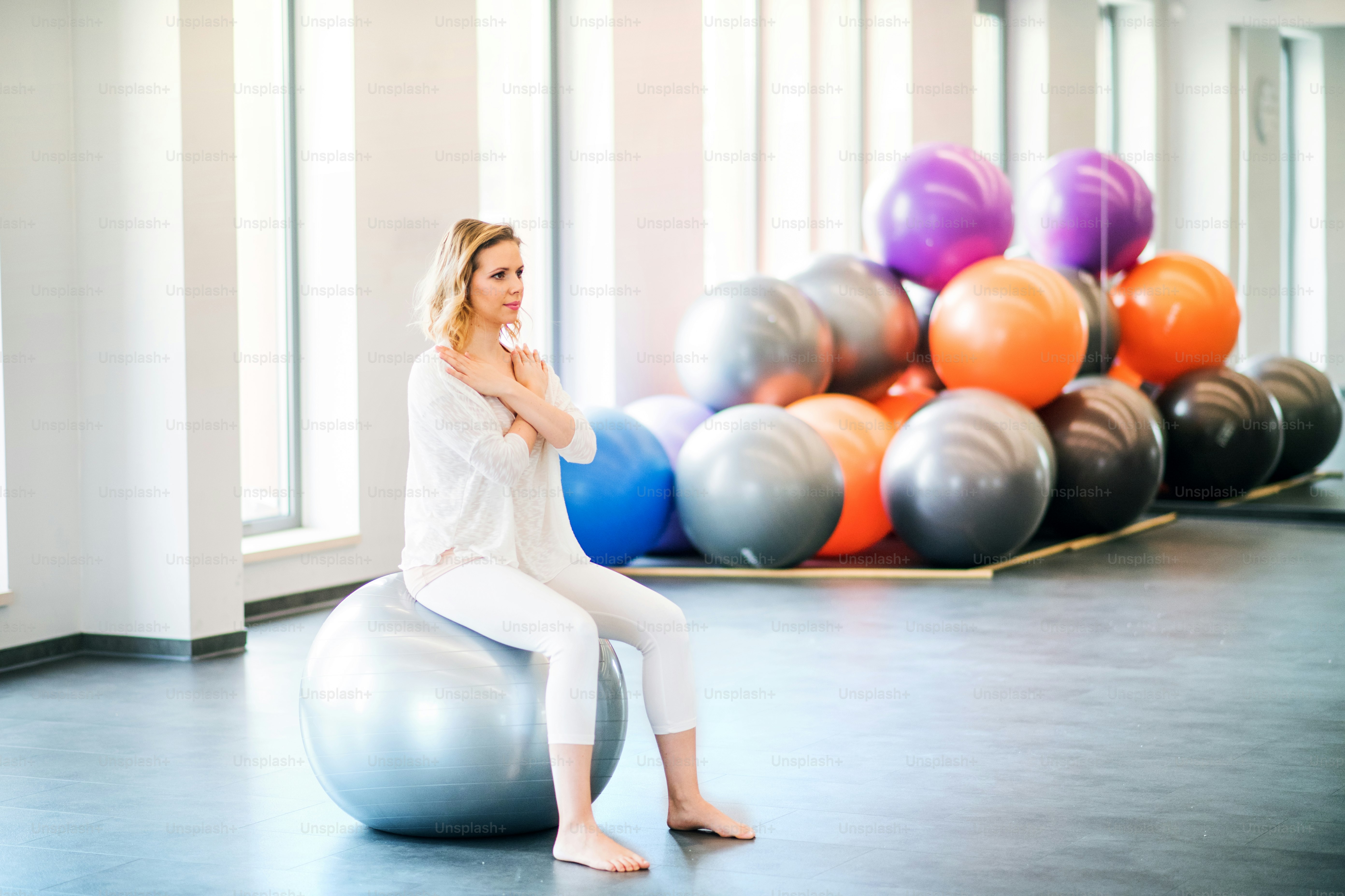 Young beautiful woman doing exercise with a fitball in a gym. photo ...
