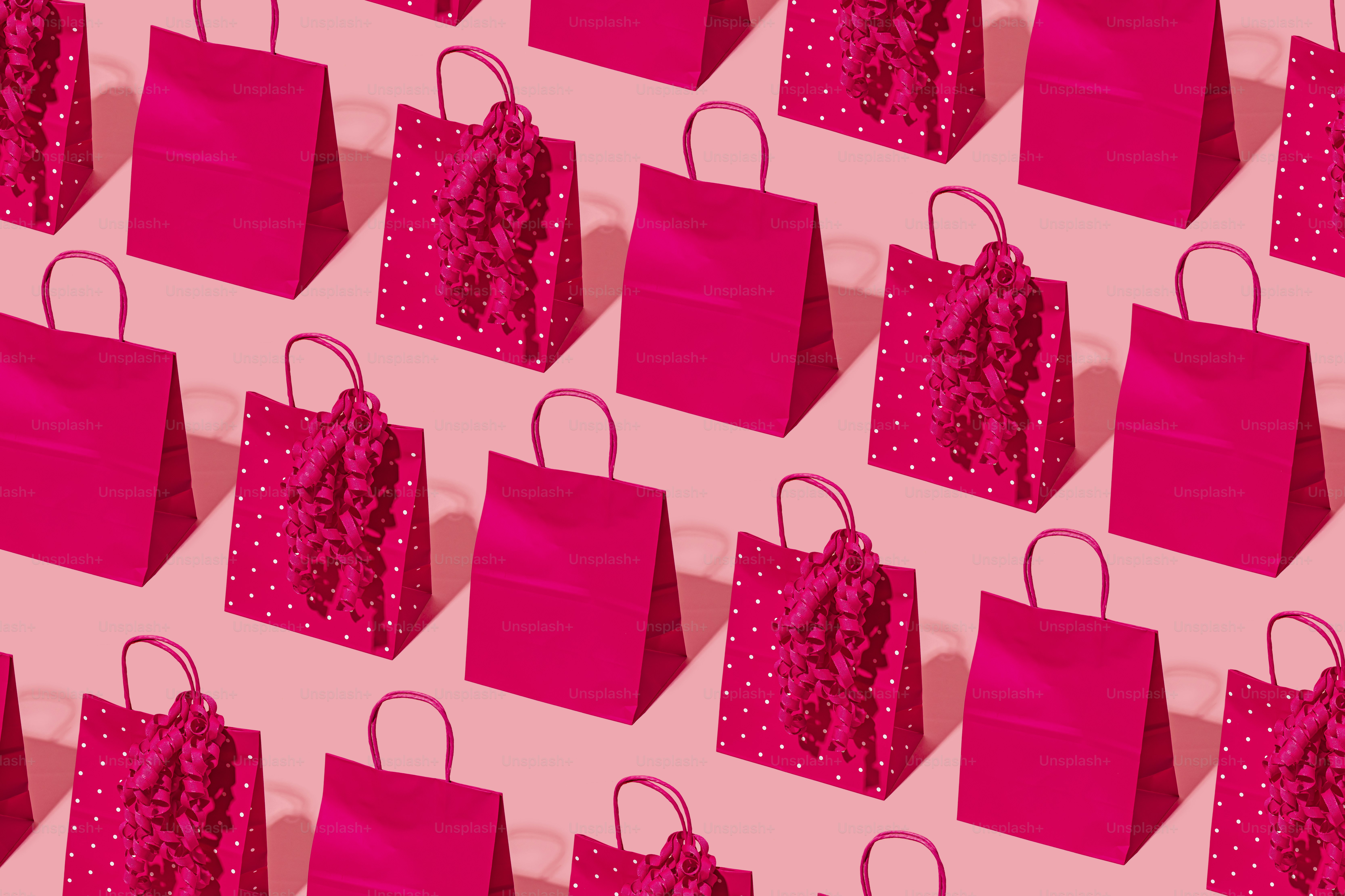 Pink shopping bags are lined up against a pink background photo ...