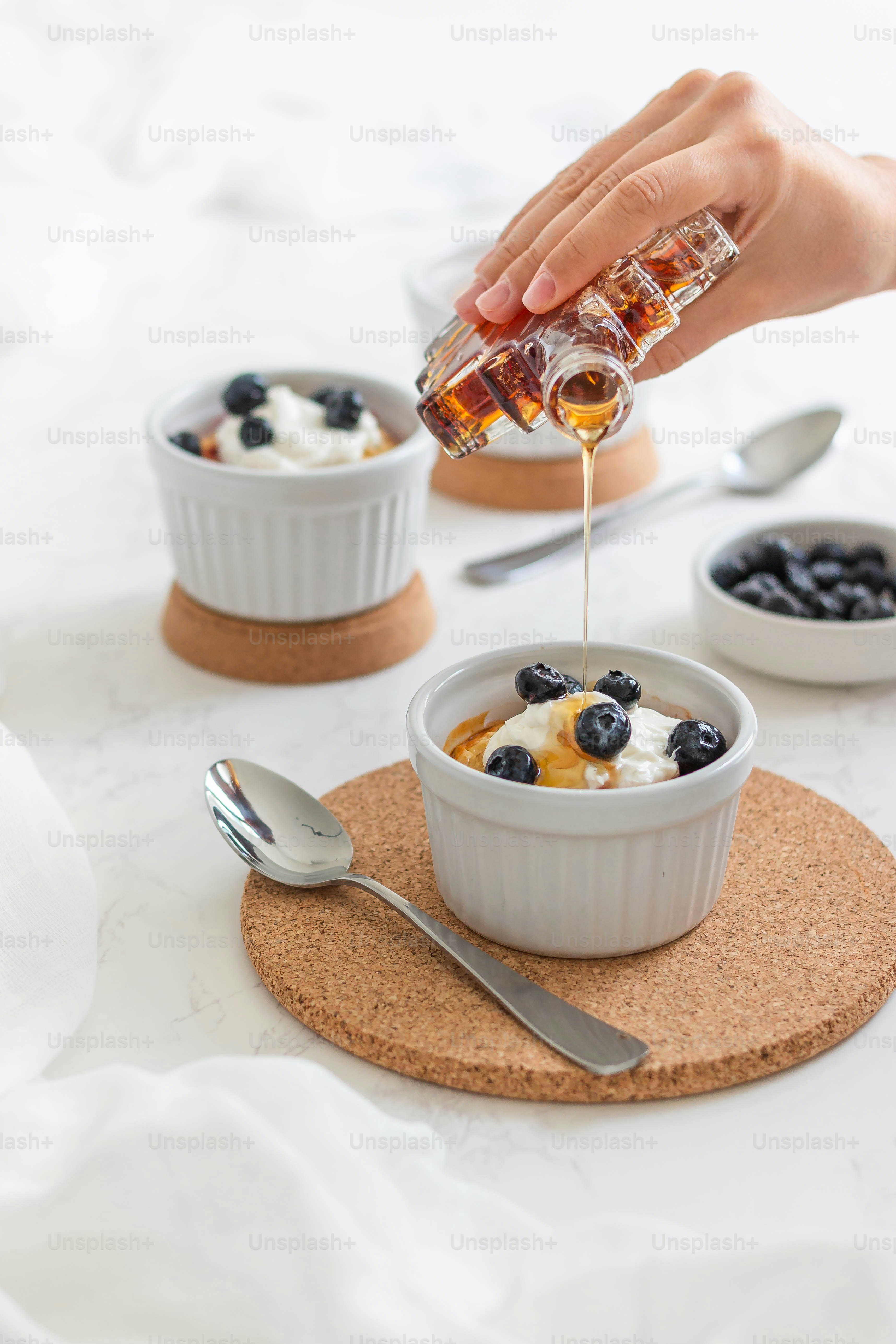 A person pouring syrup into a bowl of food photo – Maple syrup Image on ...