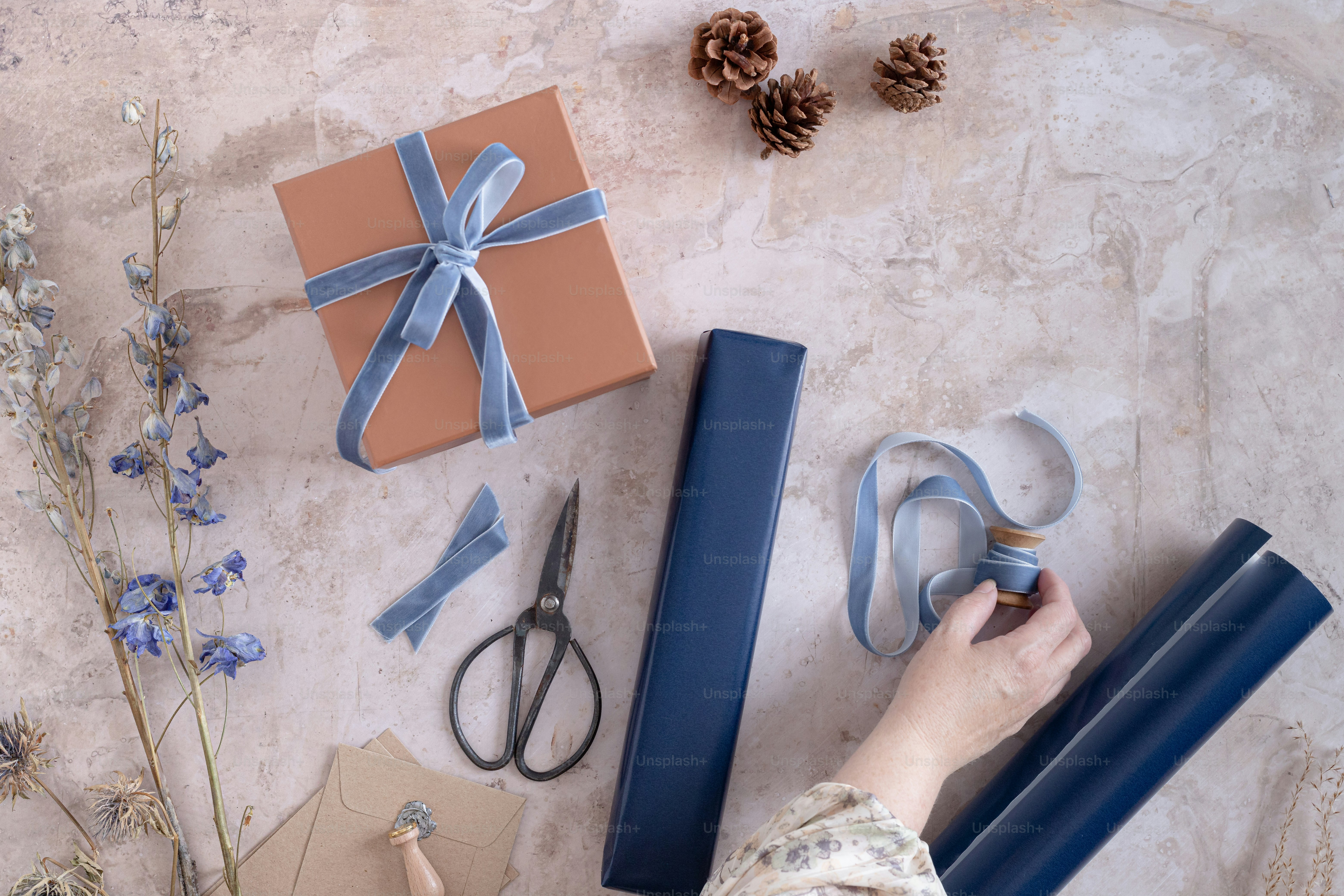 A person is wrapping a gift with a blue ribbon photo – Gifts Image on ...