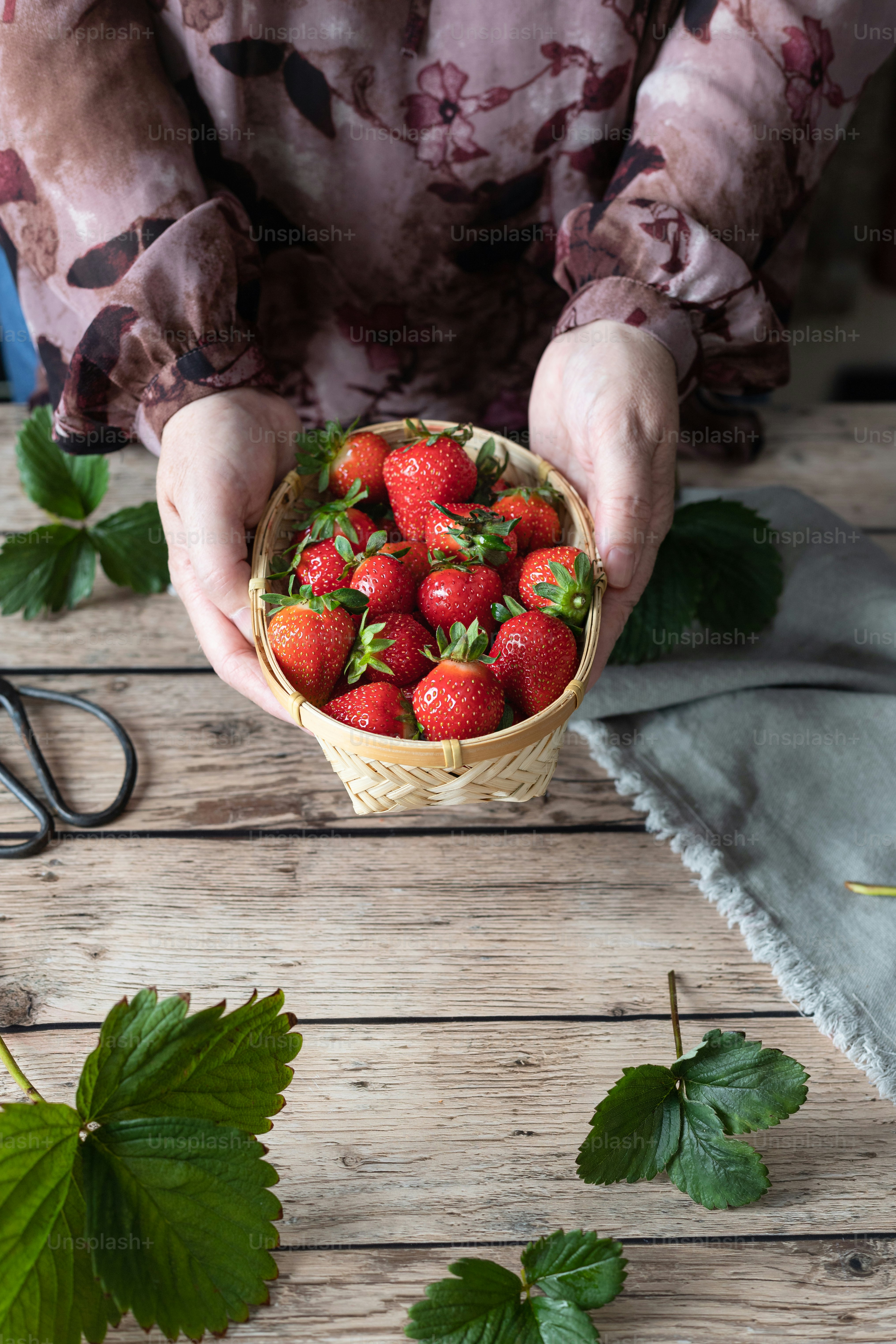 Une personne tenant un panier de fraises sur une table photo – Image de ...