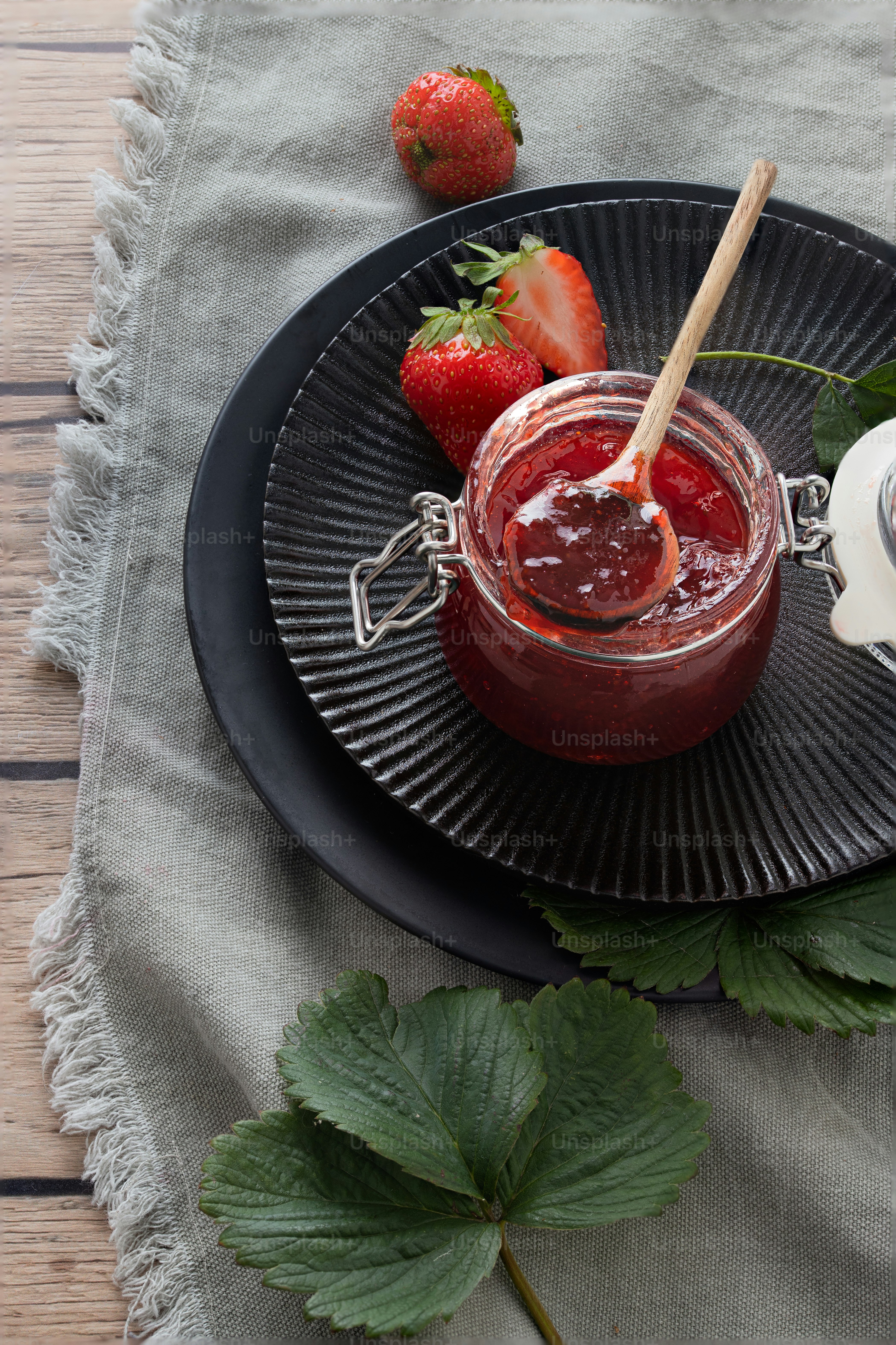 A plate with a jar of strawberry jam and two strawberries photo ...