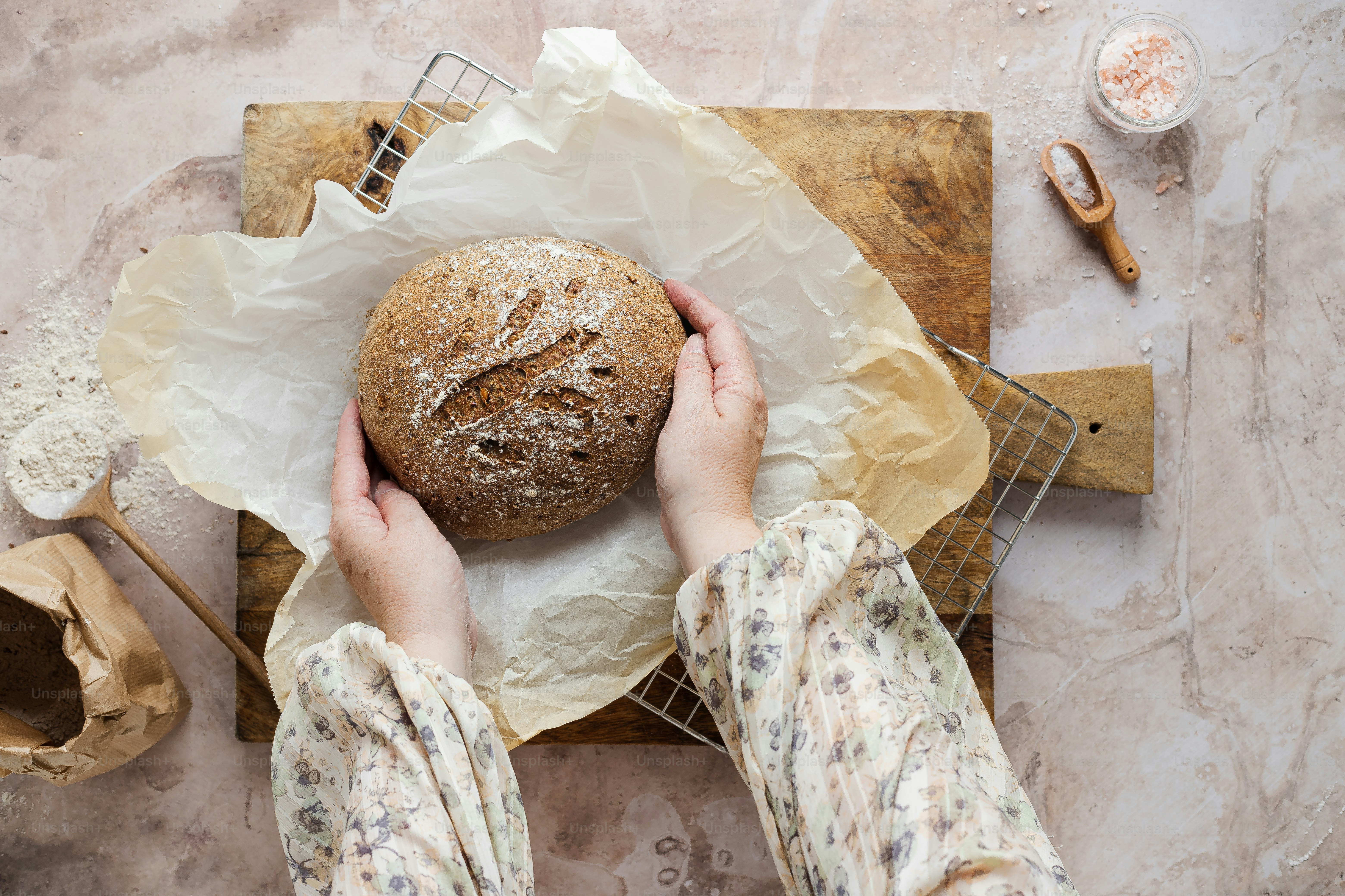 A person holding a loaf of bread on top of a table photo – Food Image ...