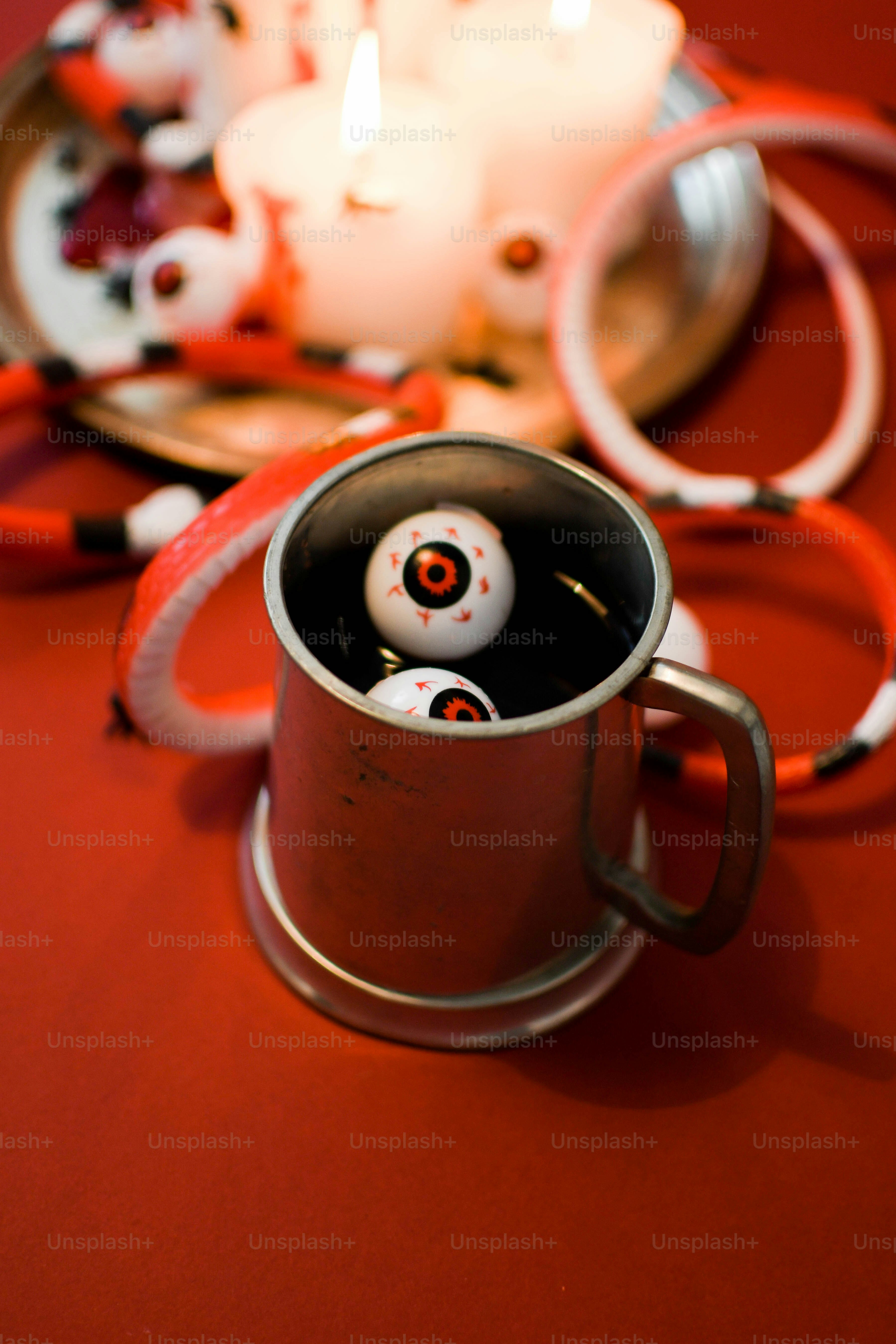 A red table topped with a cup filled with balls photo – Eyeball Image ...