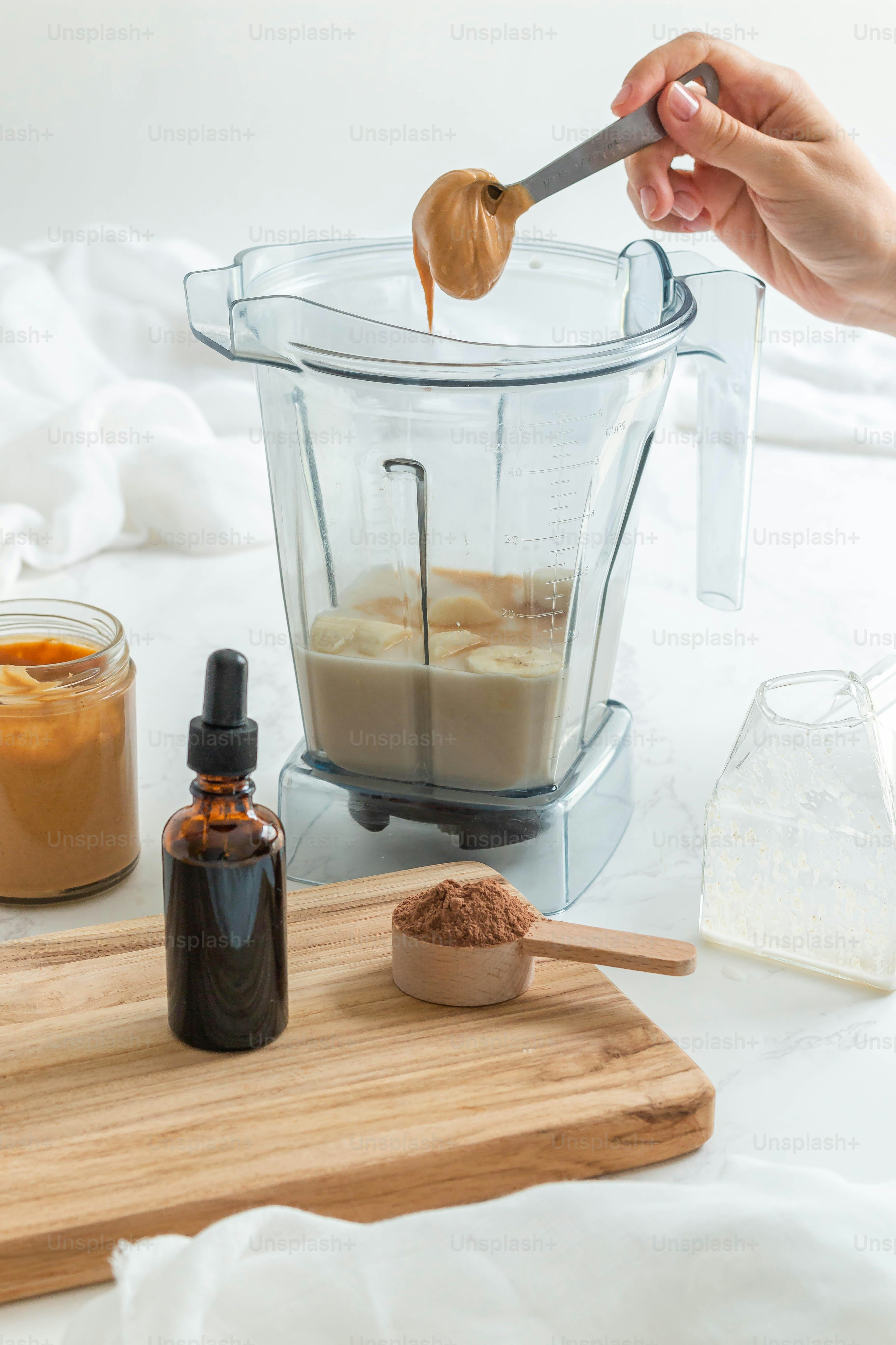 A person is using a wooden spoon to mix ingredients in a blender photo ...