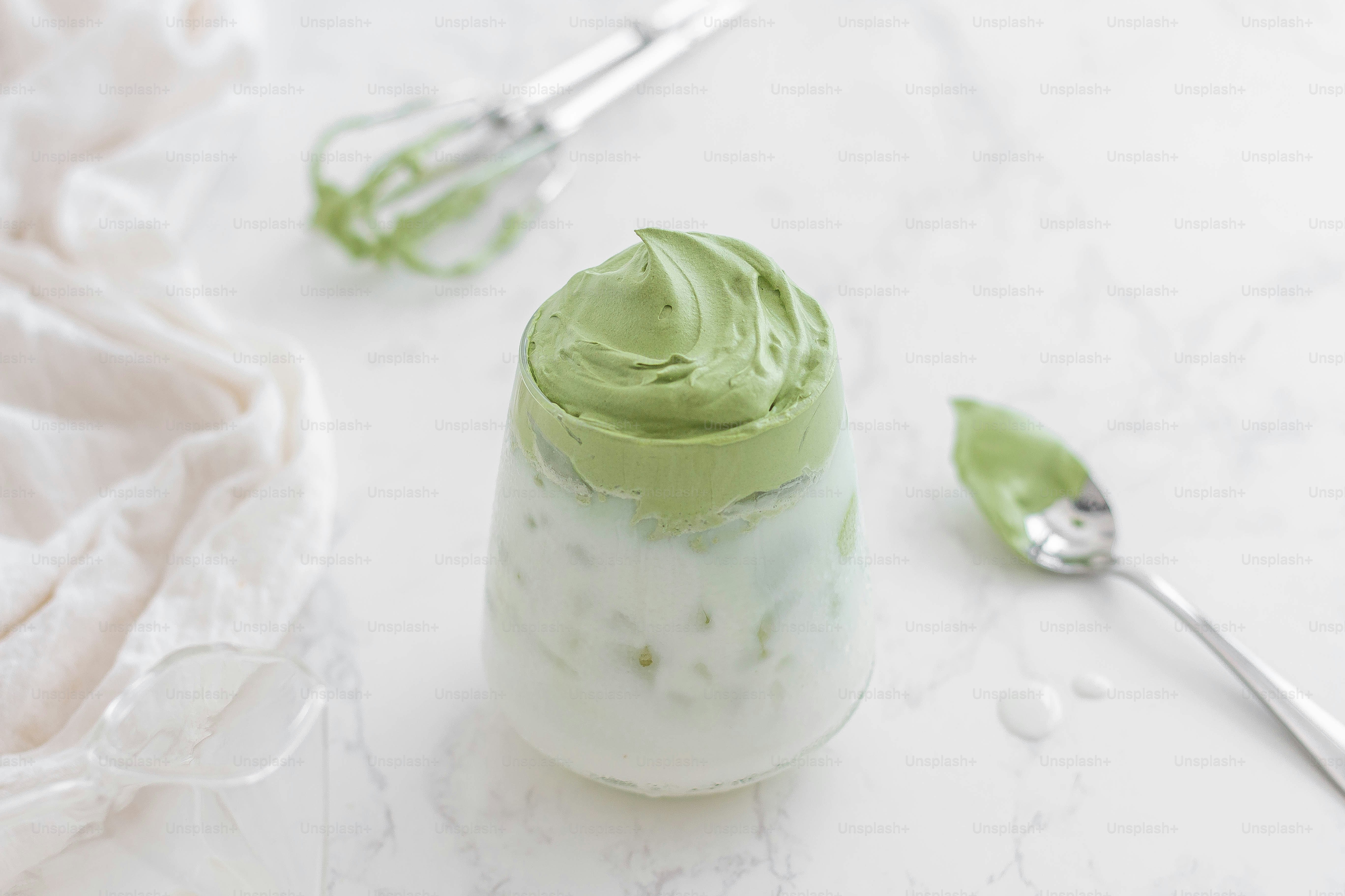 A small jar of green whipped cream next to a spoon photo – Food Image ...