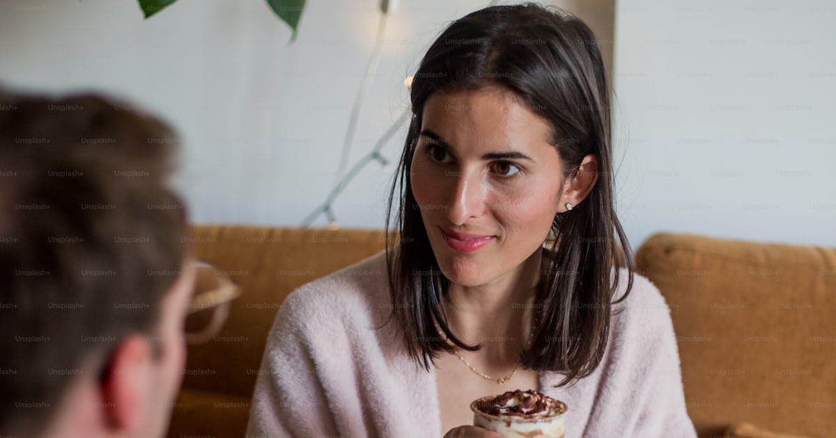 Foto zum Thema Eine Frau, die auf einer Couch sitzt und eine Tasse ... Foto zum Thema Eine Frau, die auf einer Couch sitzt und eine Tasse ...