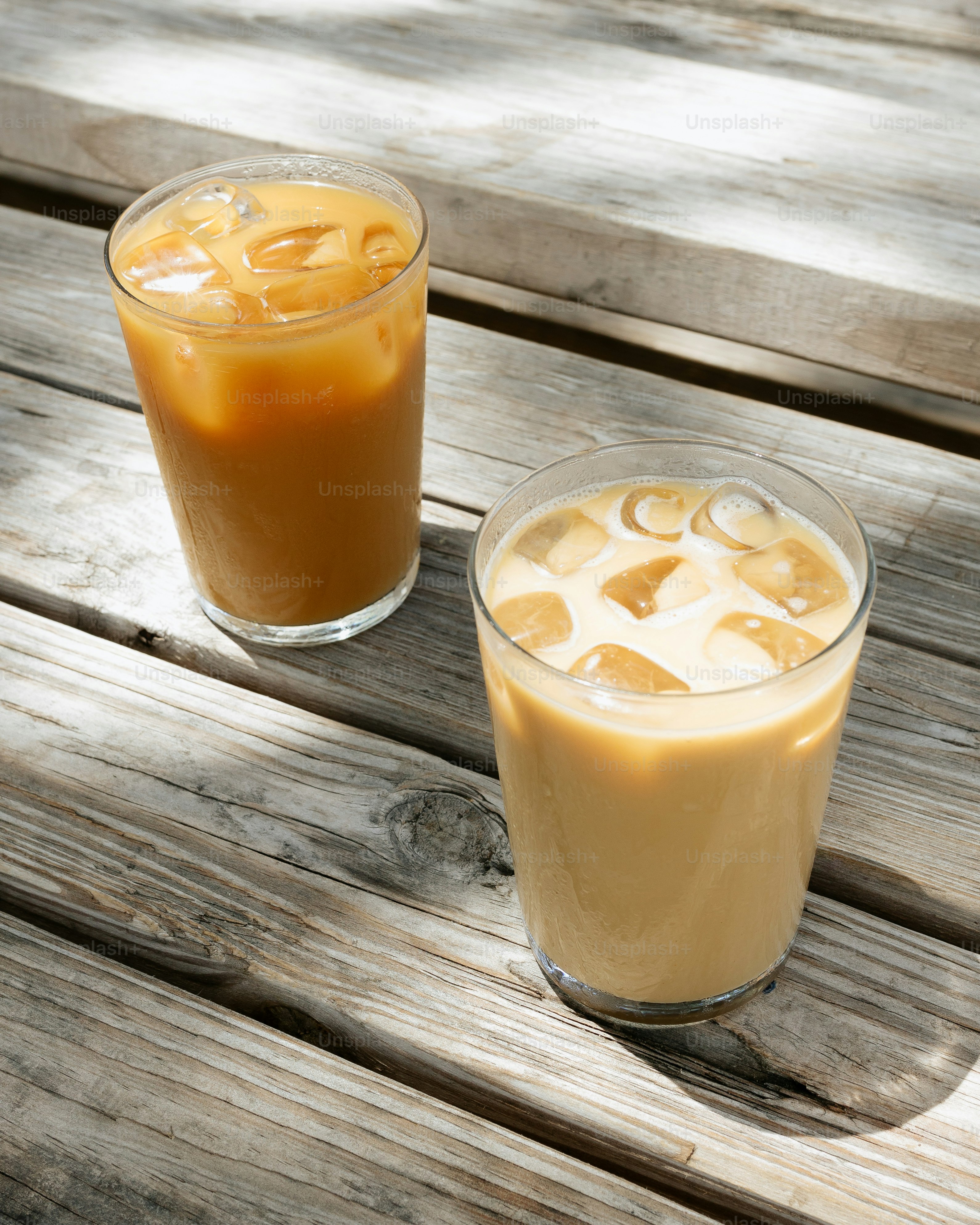 Two glasses of iced coffee sitting on top of a wooden table photo ...