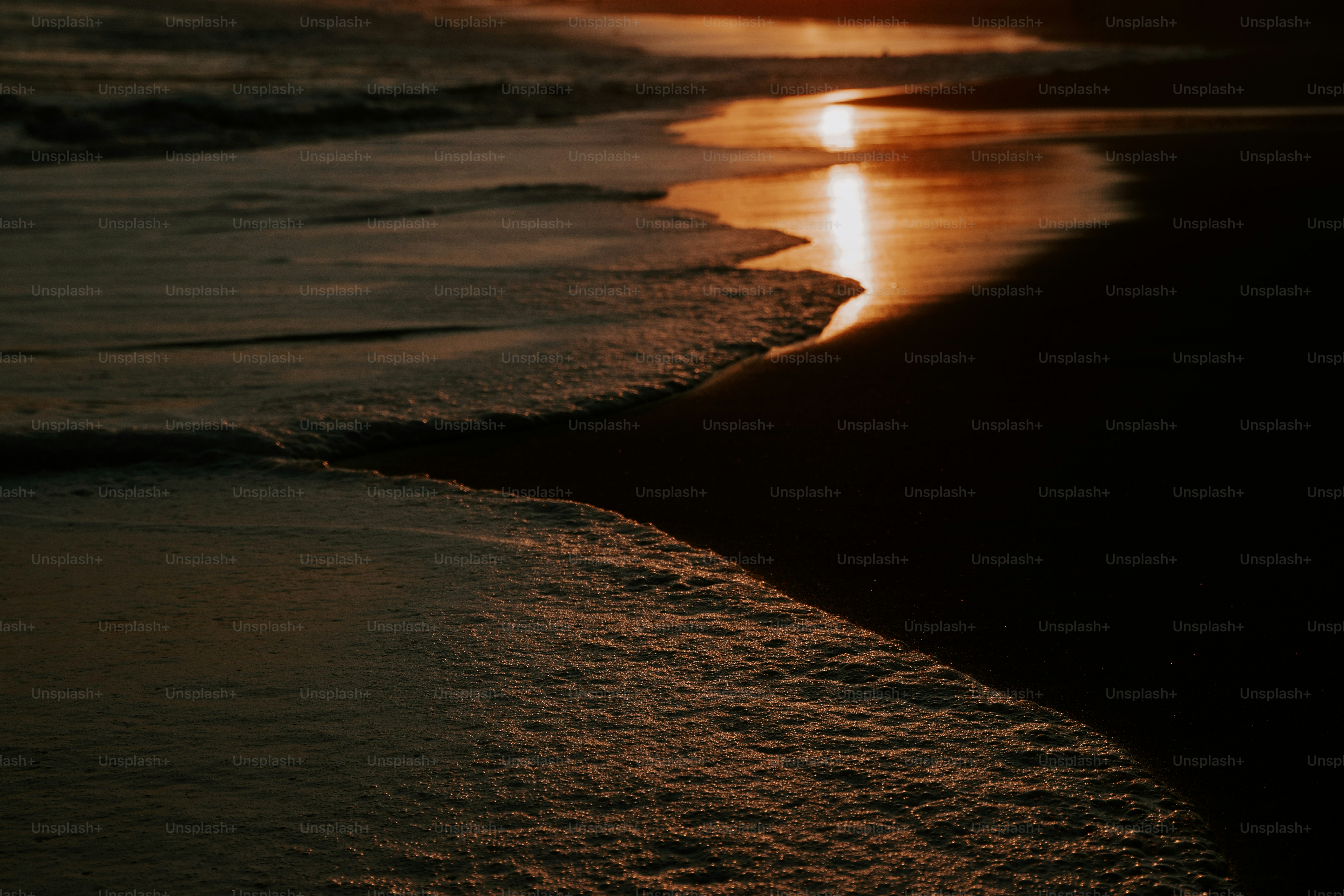 The sun is setting over the water at the beach photo – Sand Image on ...