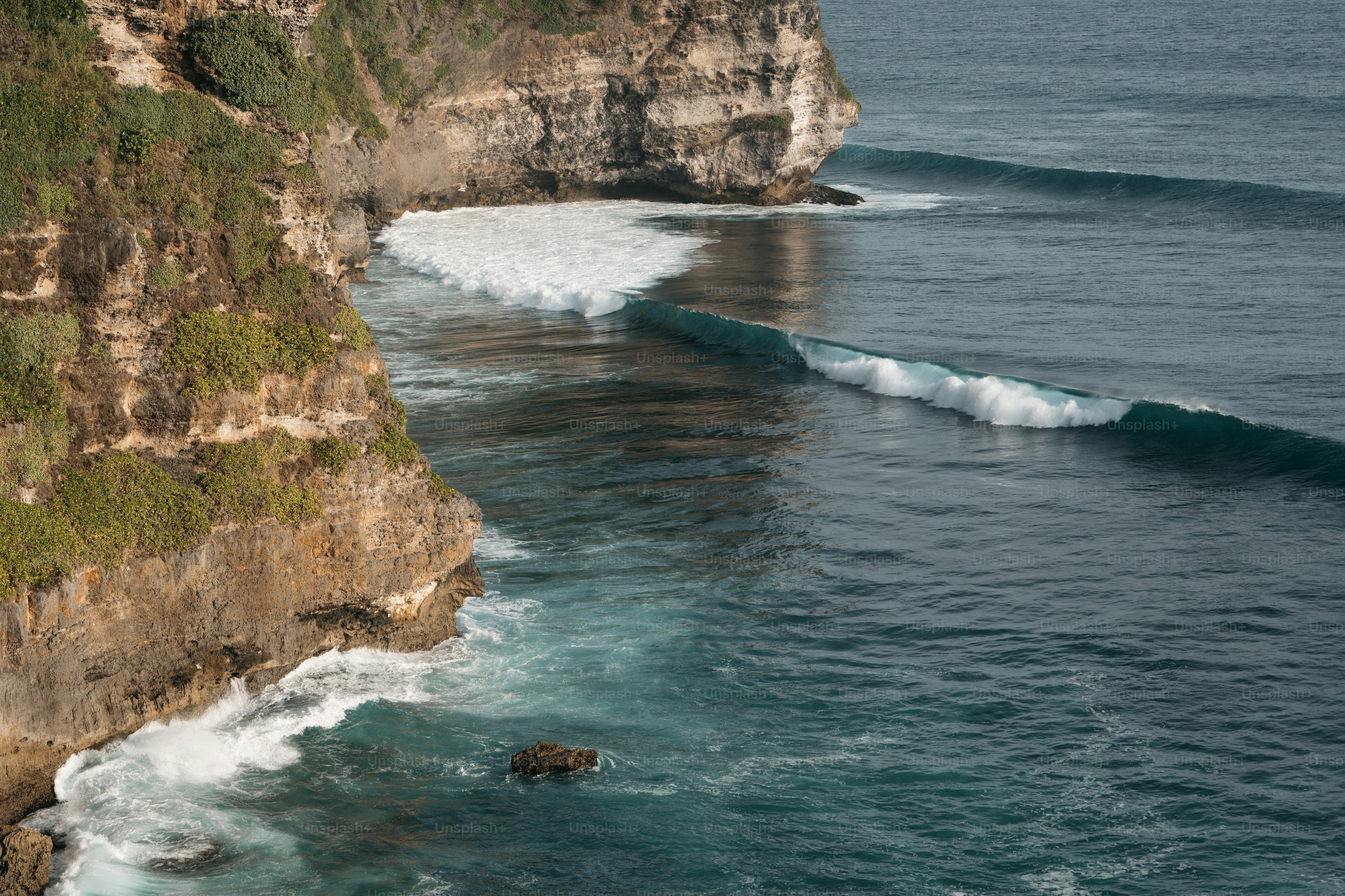 A cliff with a wave coming in from the ocean photo – Wave Image on Unsplash