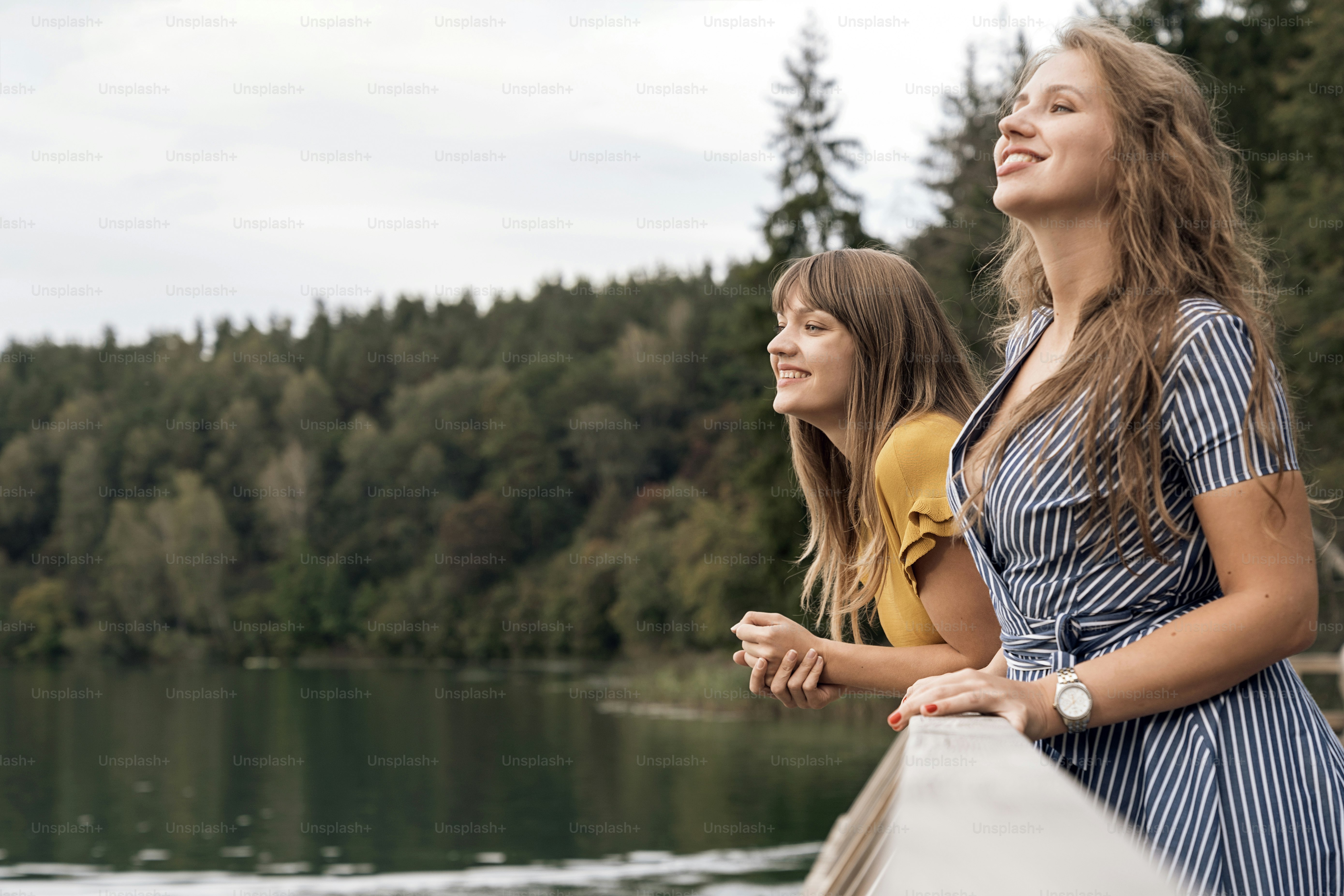 Side view of dreaming women standing on wooden pier in green nature ...