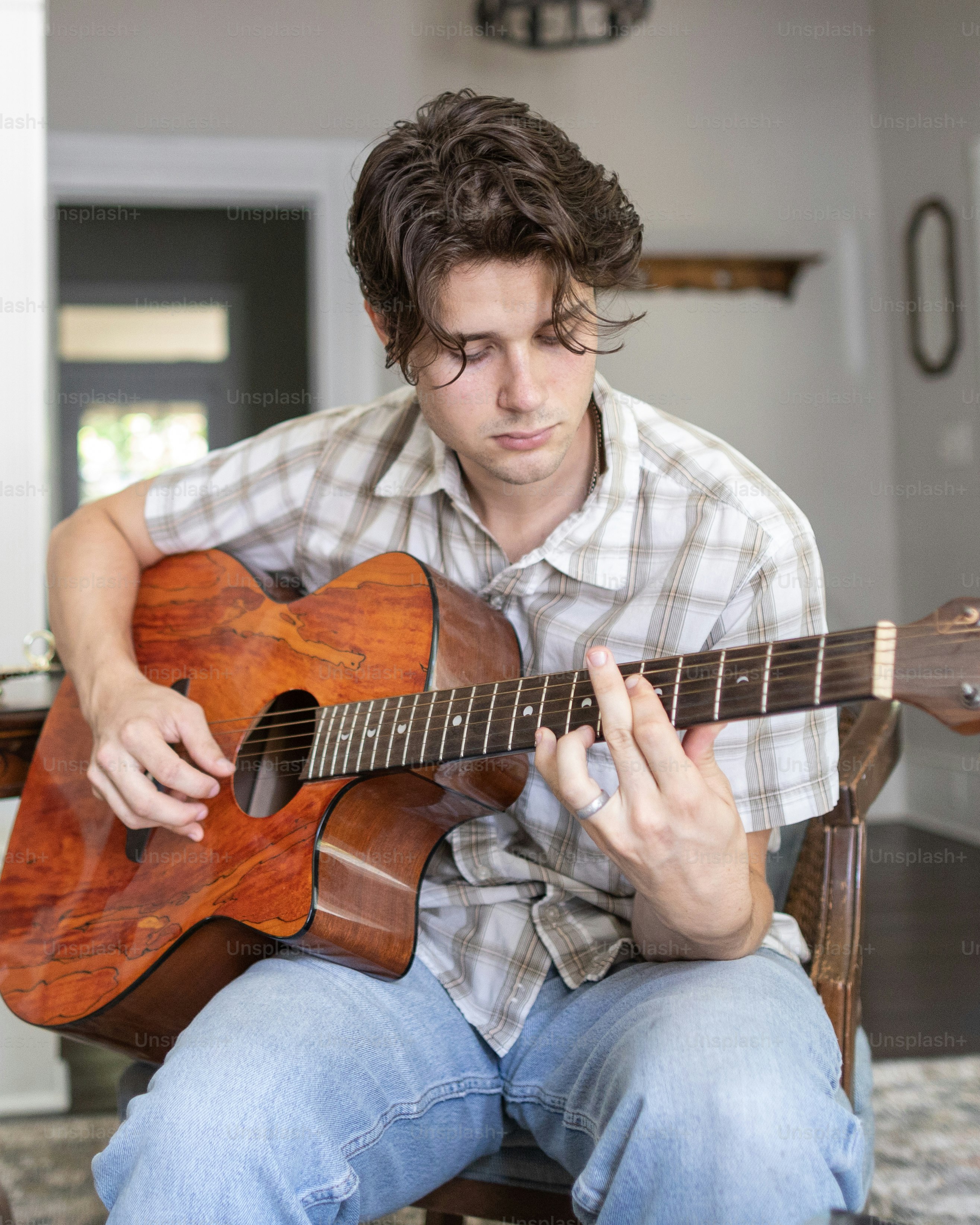 A man sitting on a chair playing a guitar photo – Talent Image on Unsplash