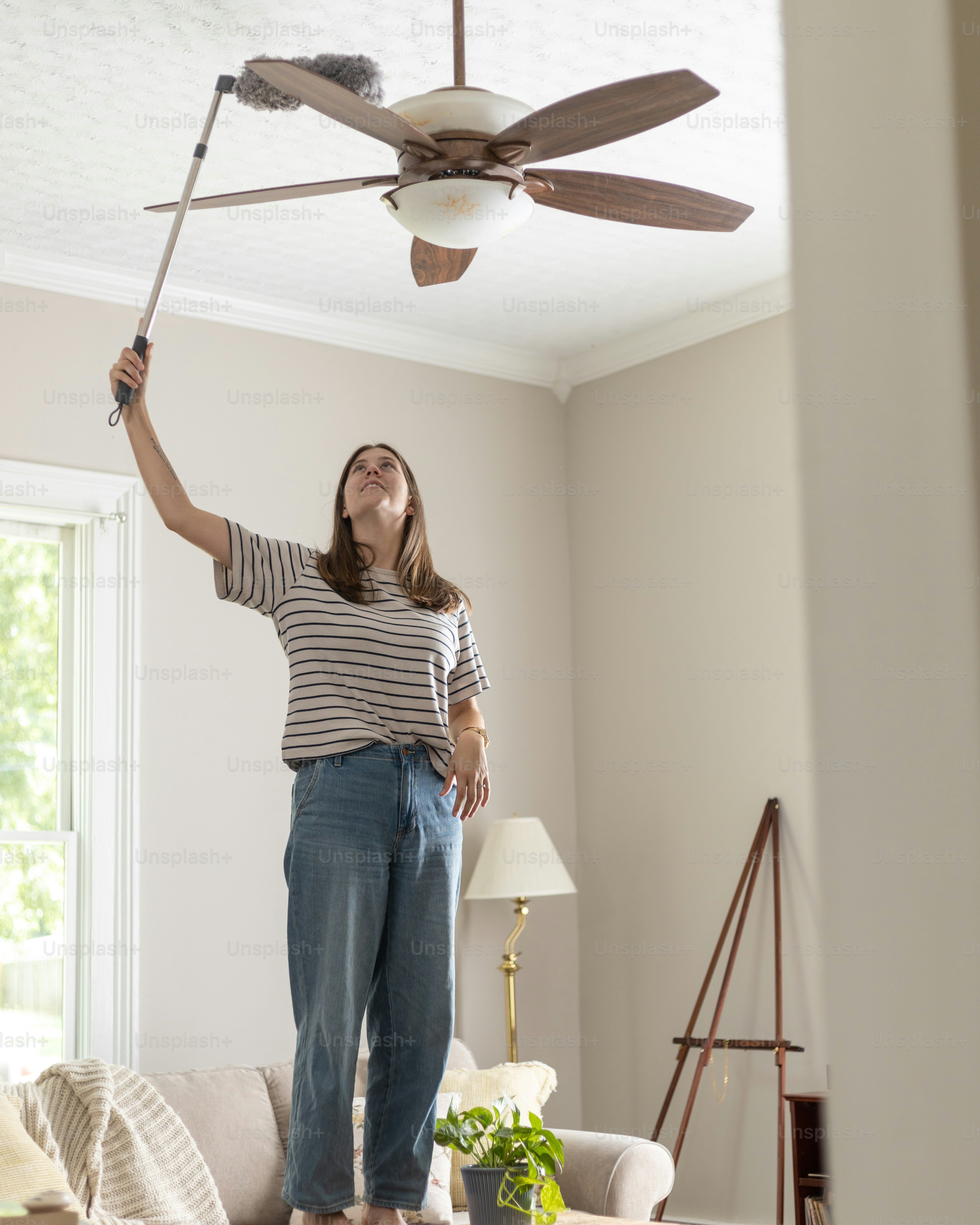 A woman standing in a living room holding a ceiling fan photo – Ceiling ...