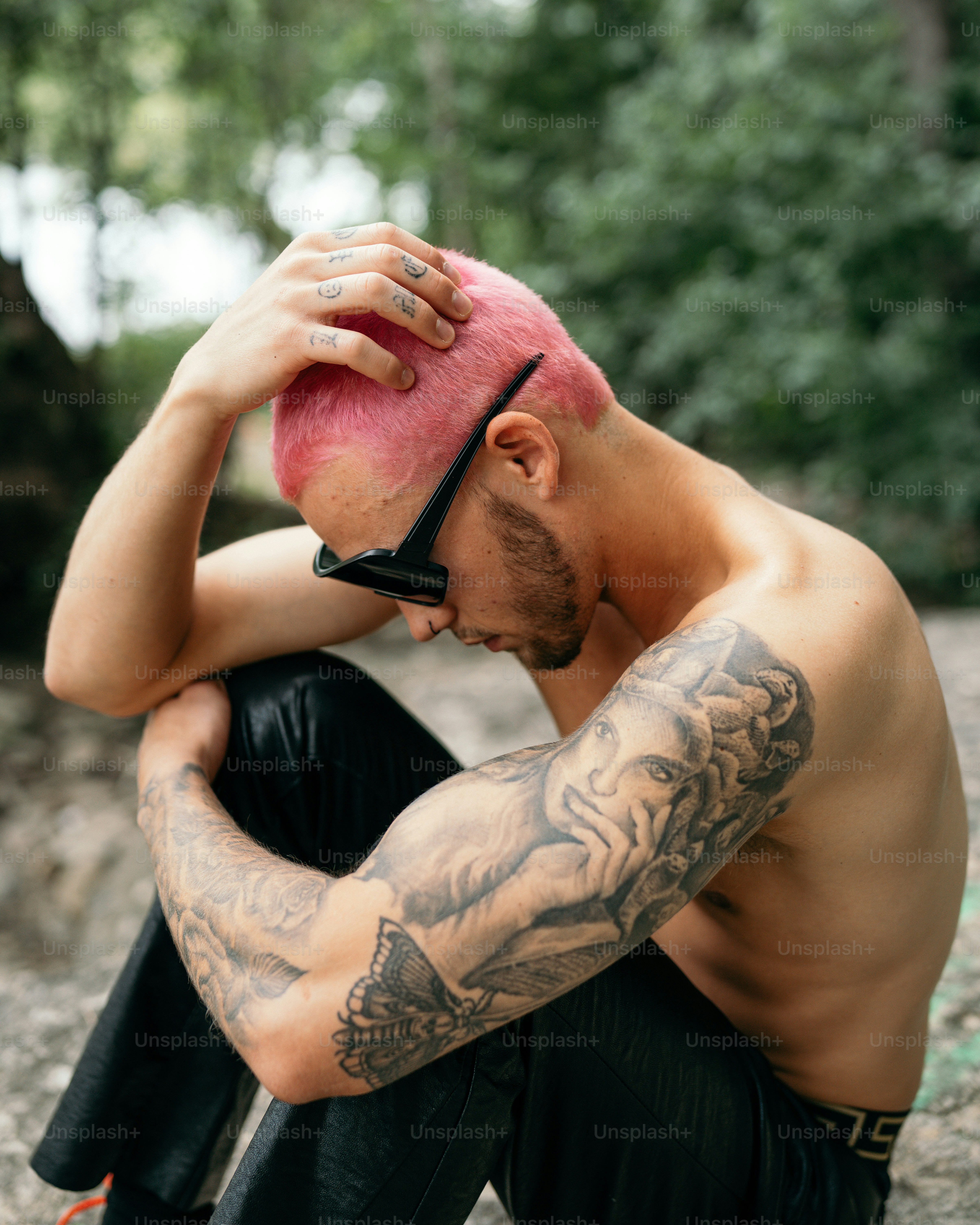 A man with a pink mohawk sitting on a rock photo – Male Image on Unsplash