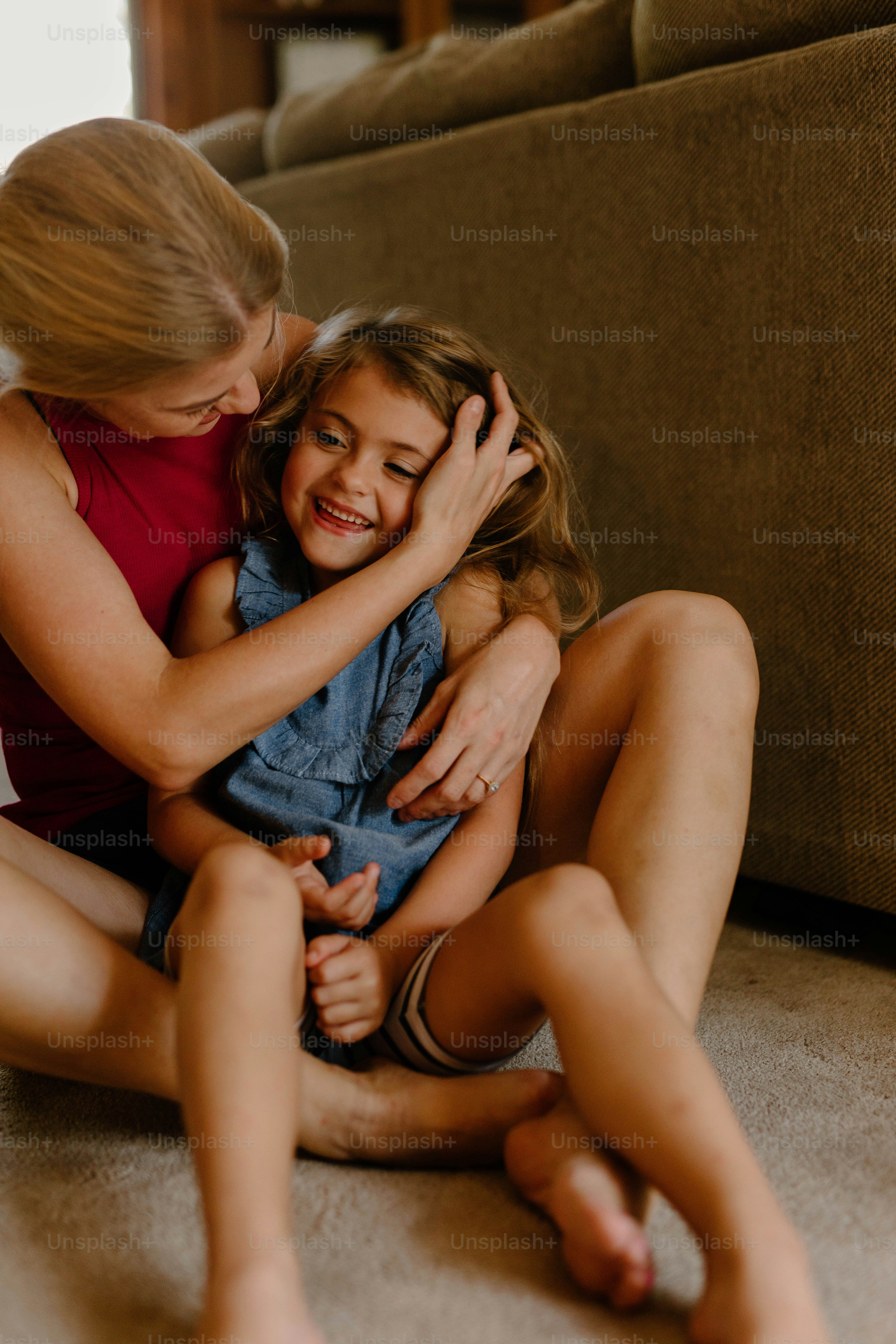 A woman sitting on the floor hugging a little girl photo – Cheer up ...