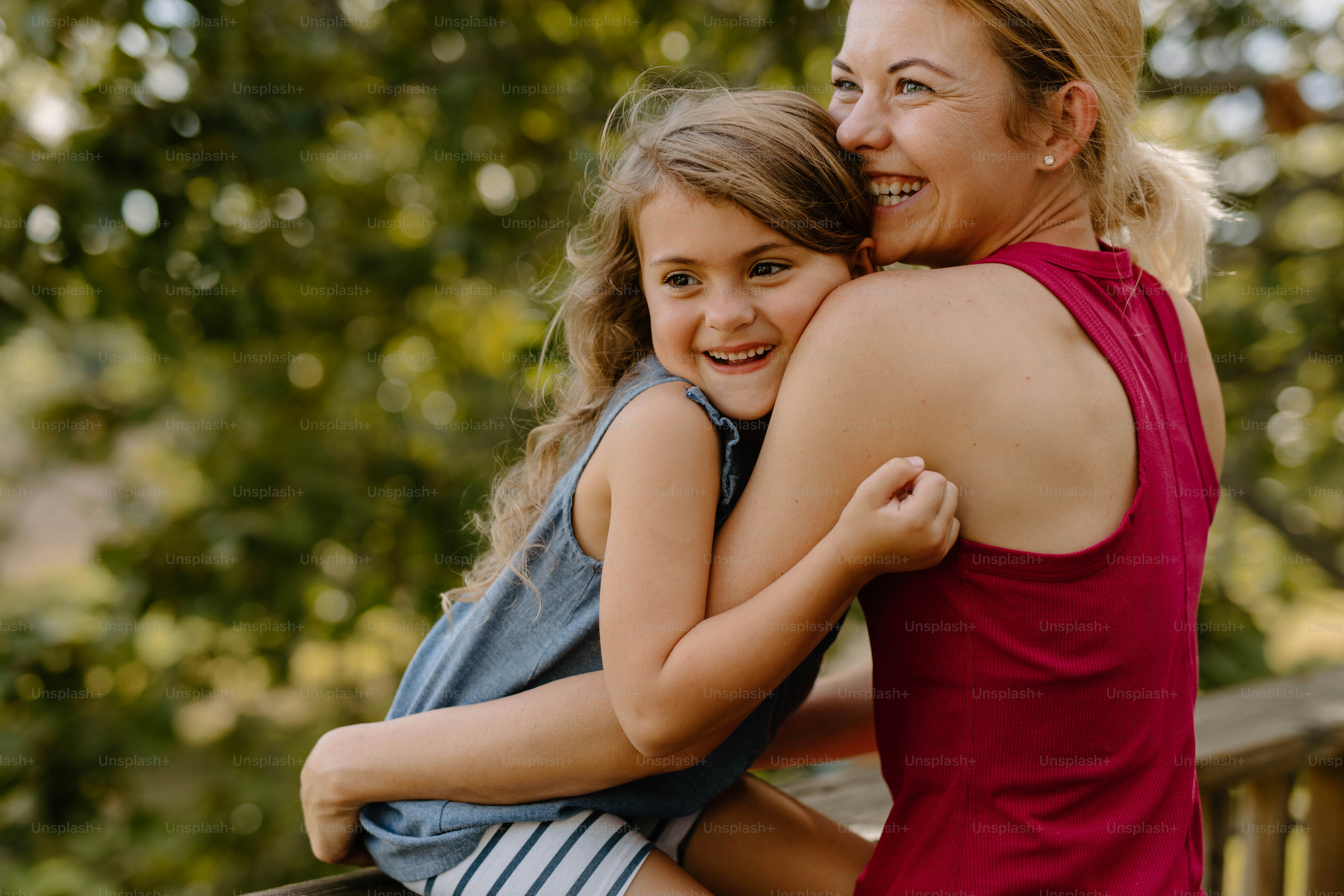 A woman hugging a little girl on a bench photo – Babysitting Image on ...