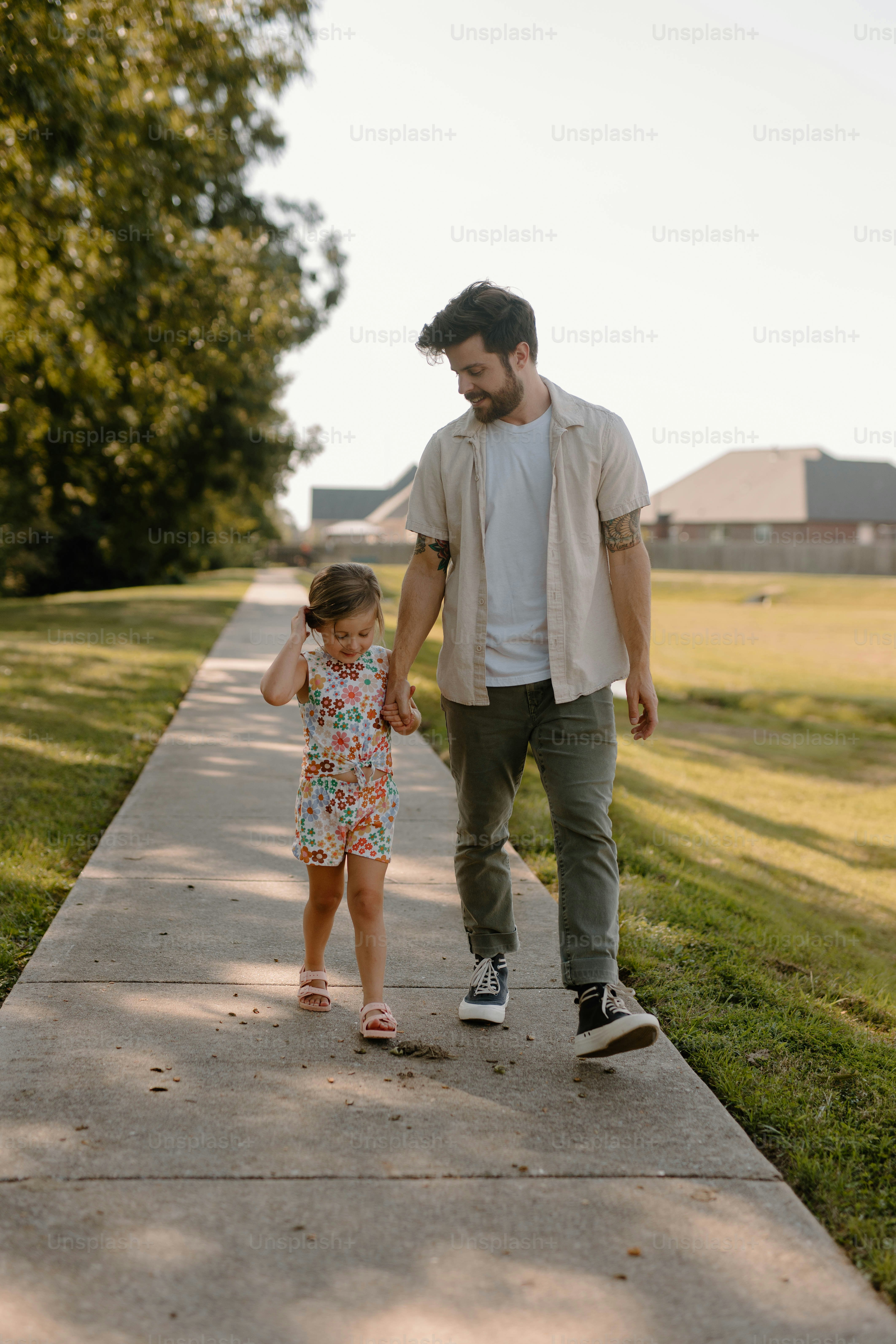A man and a little girl walking down a sidewalk photo – Dad Image on ...