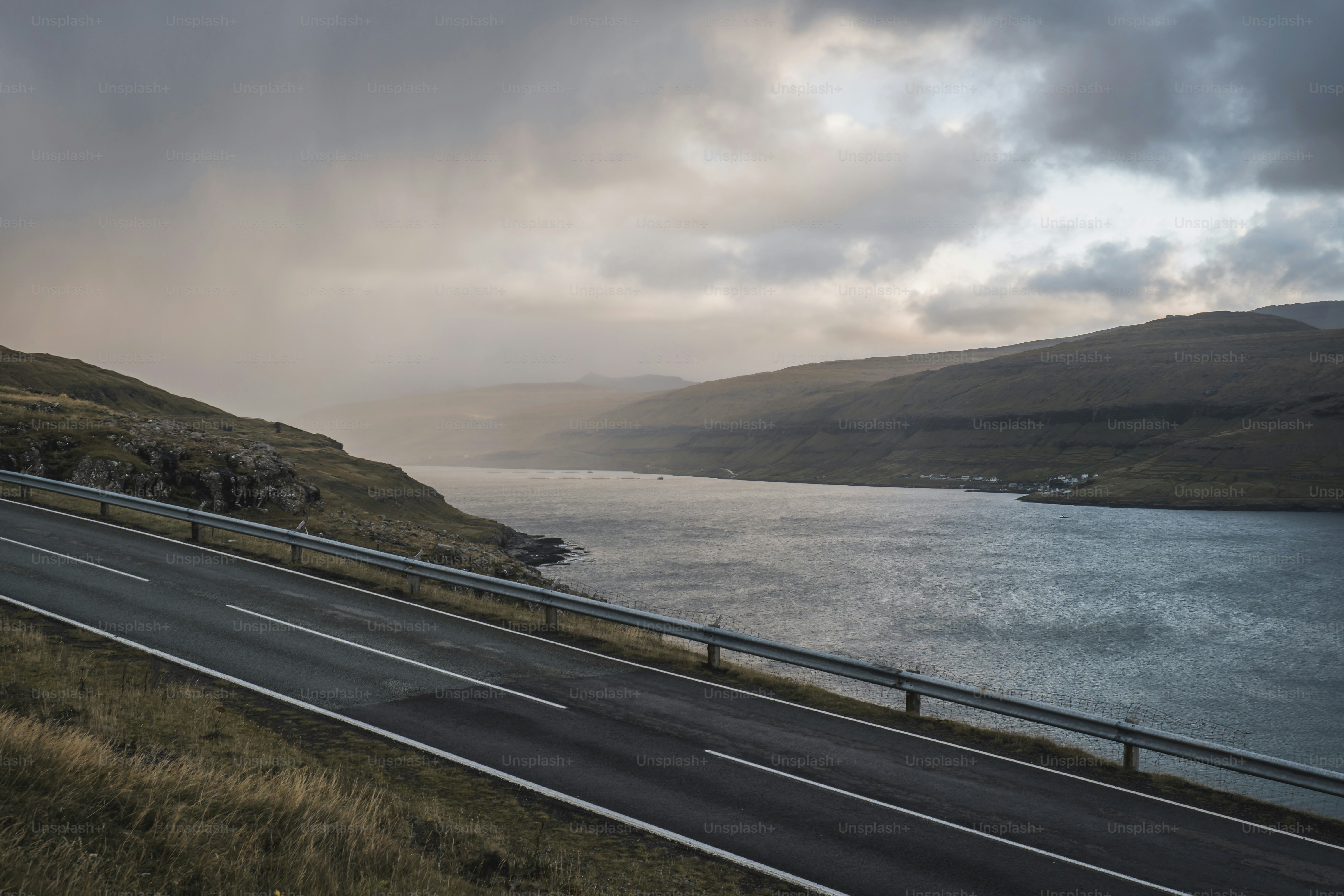 A highway with a body of water in the distance photo – Faroe islands ...