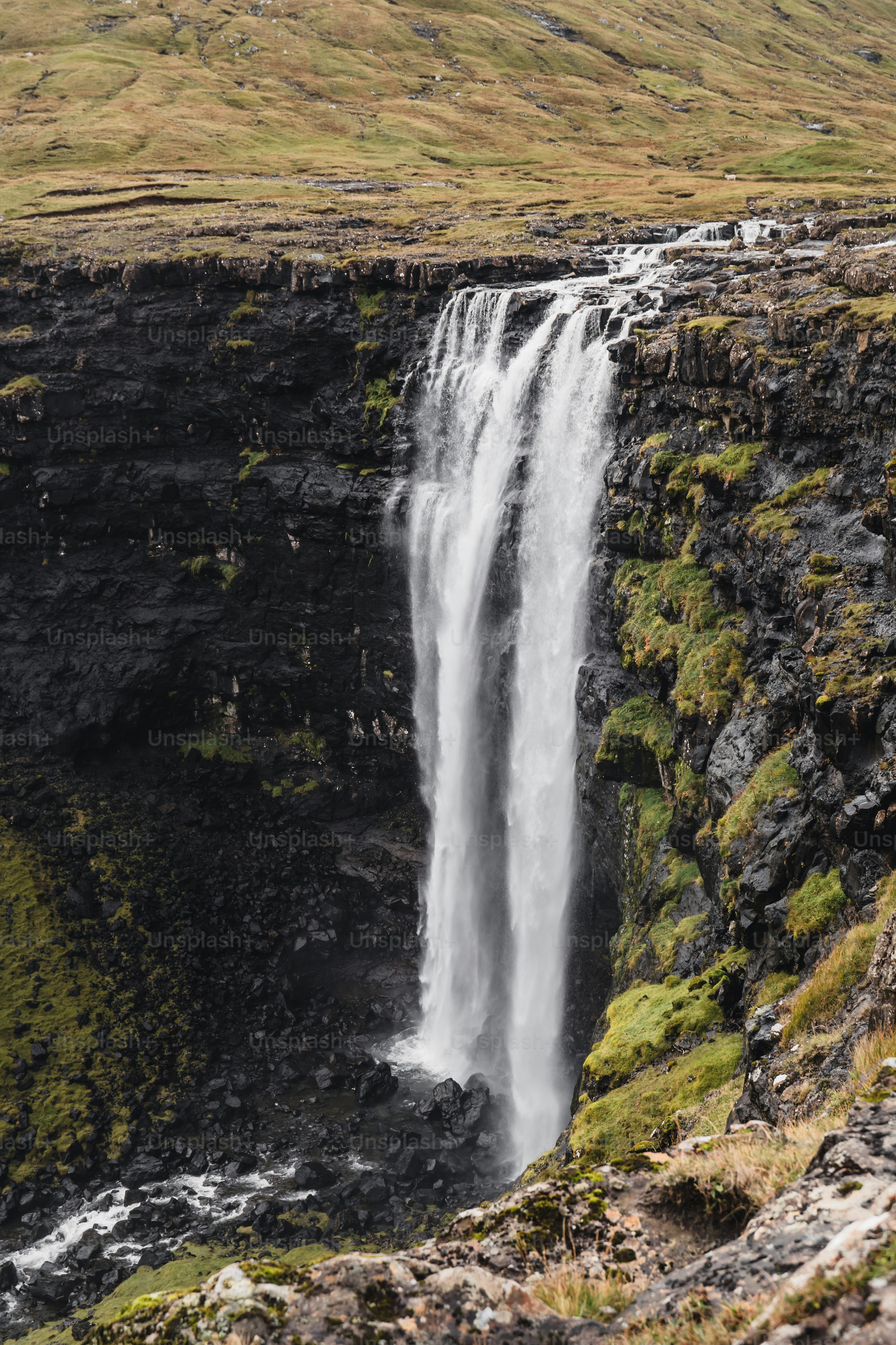 A very tall waterfall with a bunch of water coming out of it photo ...