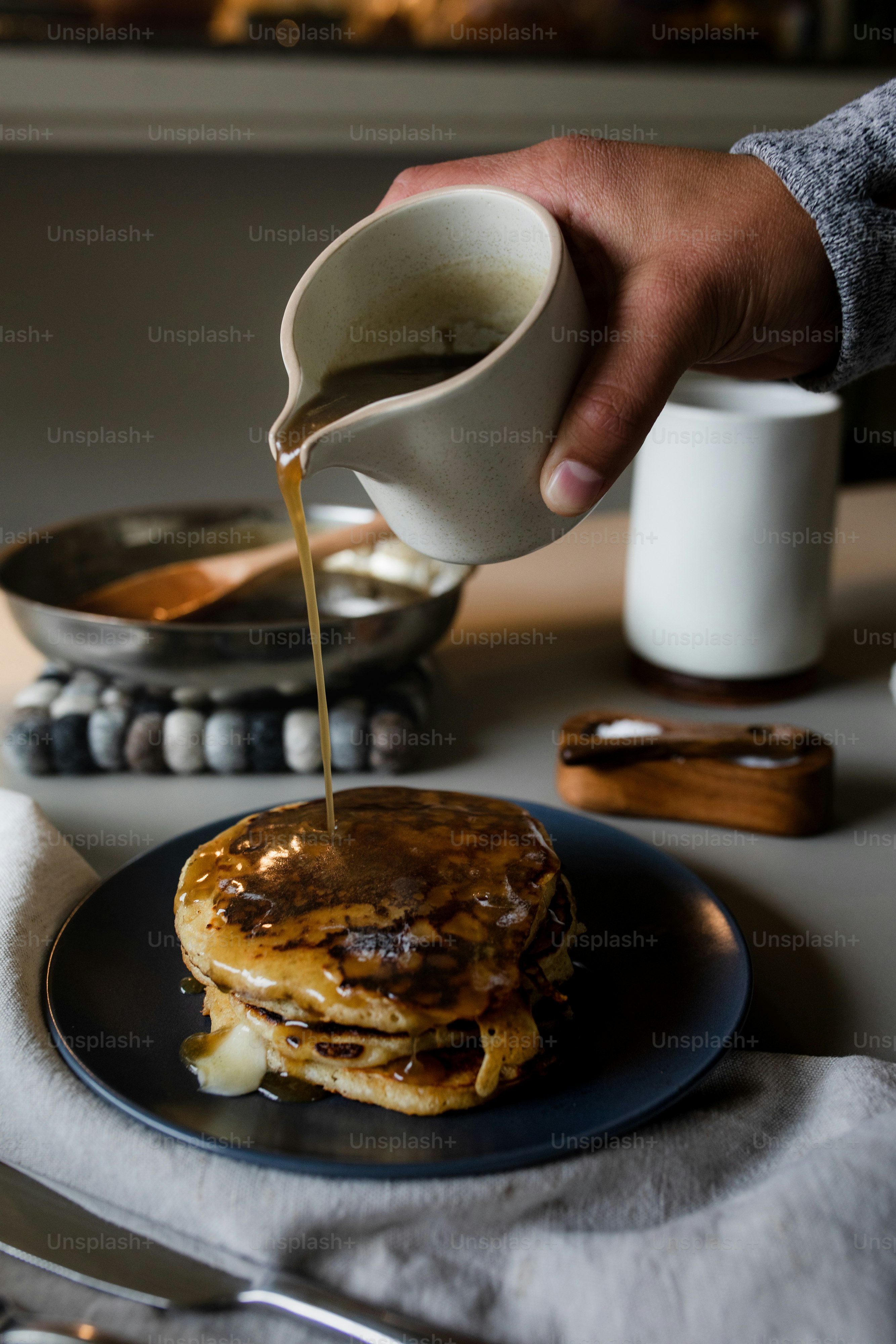 A person pouring syrup on a stack of pancakes photo – Maple syrup Image ...