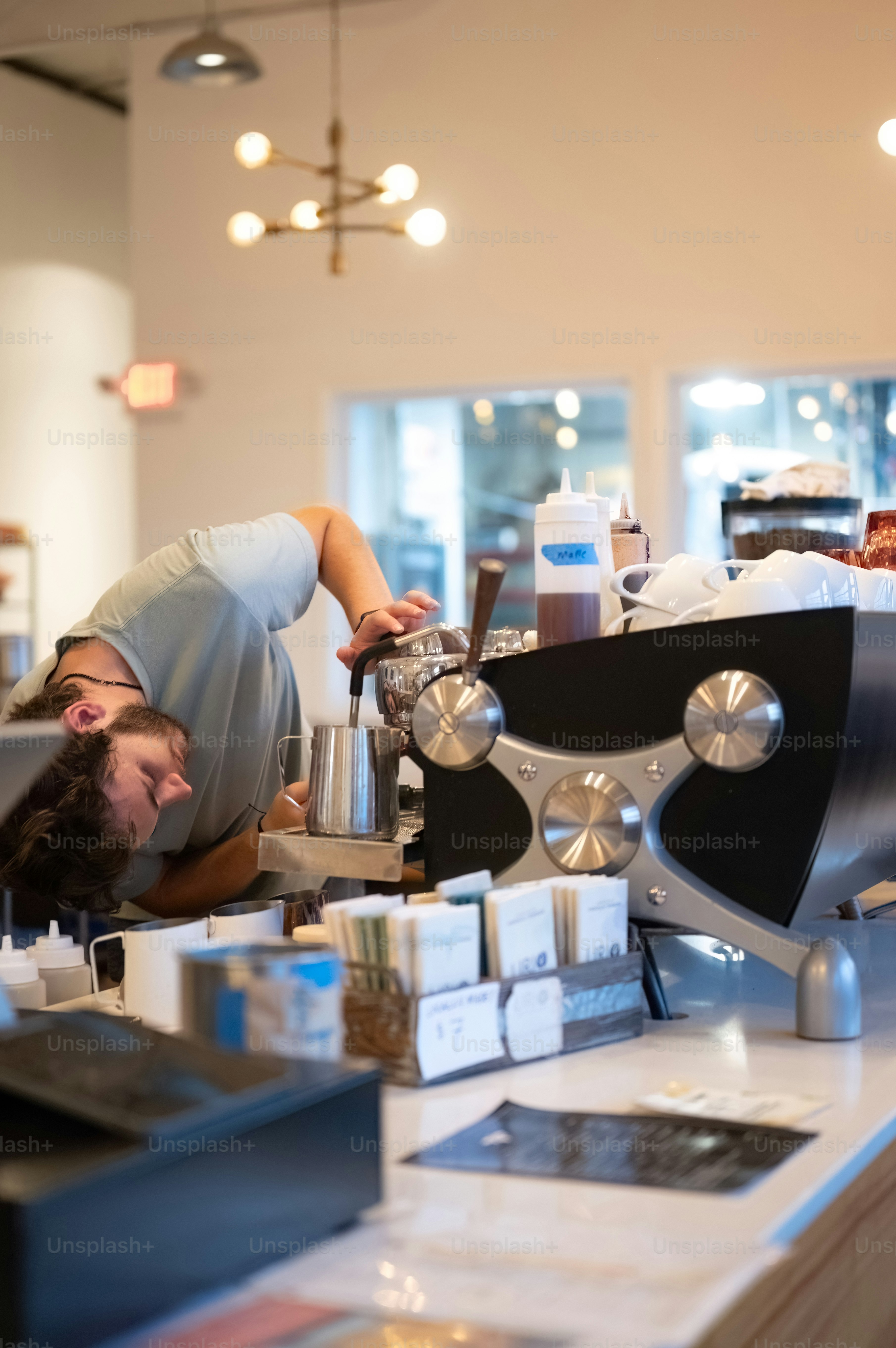 A man leaning over a counter in a store photo – Coffee brewing Image on ...