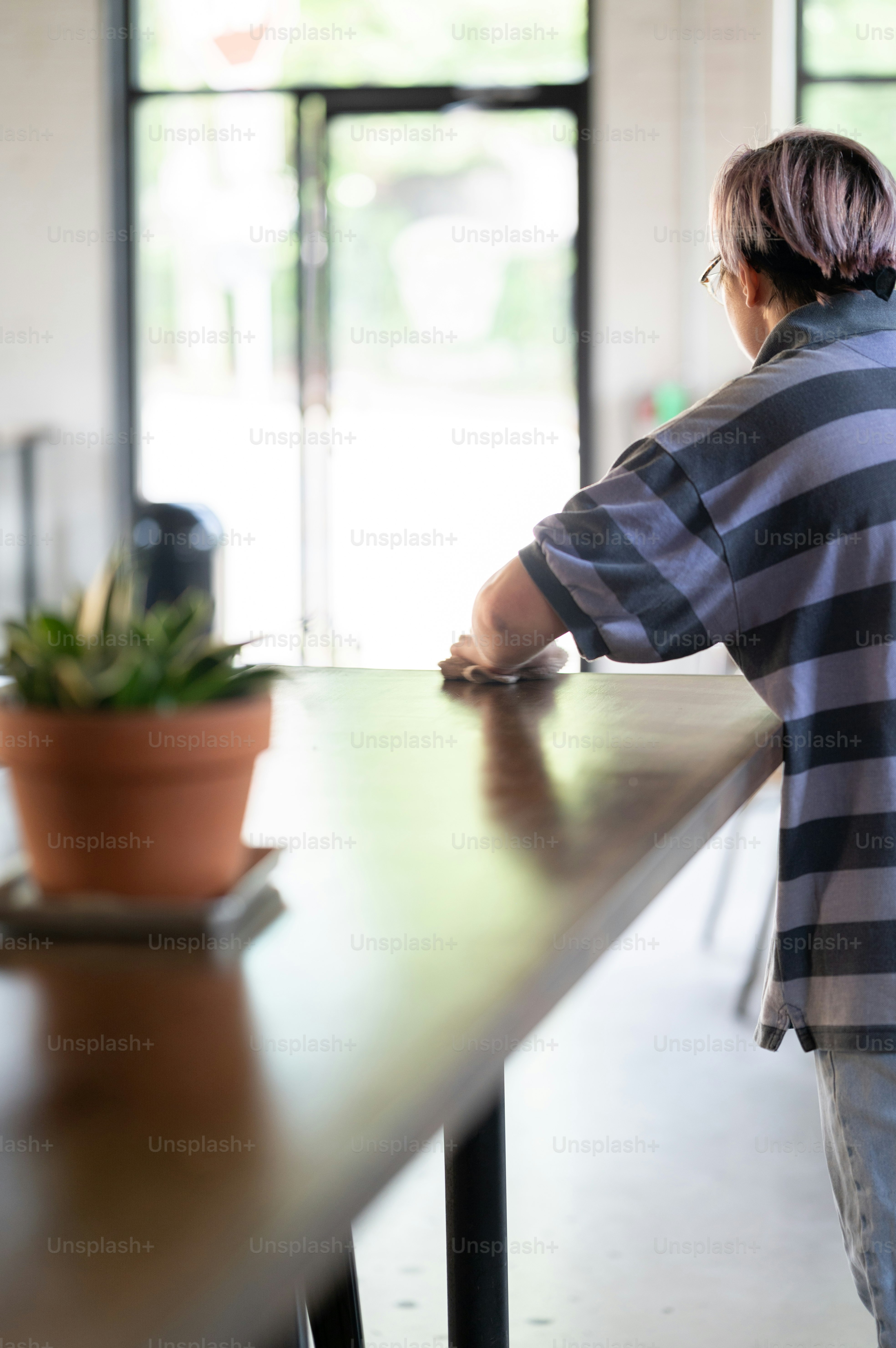 A person standing at a table with a potted plant photo – Person Image ...