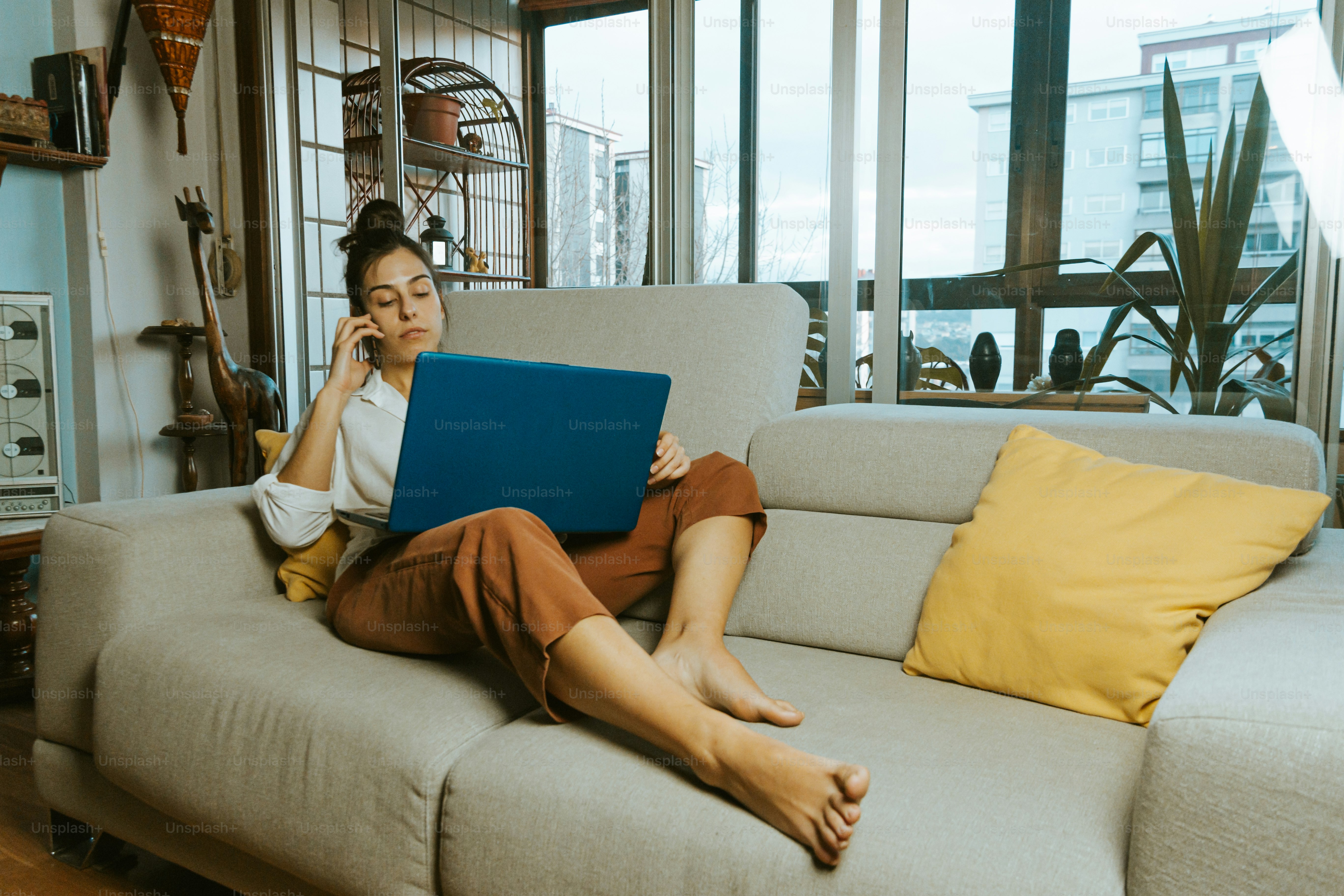 A woman sitting on a couch using a laptop computer photo – Blogger ...