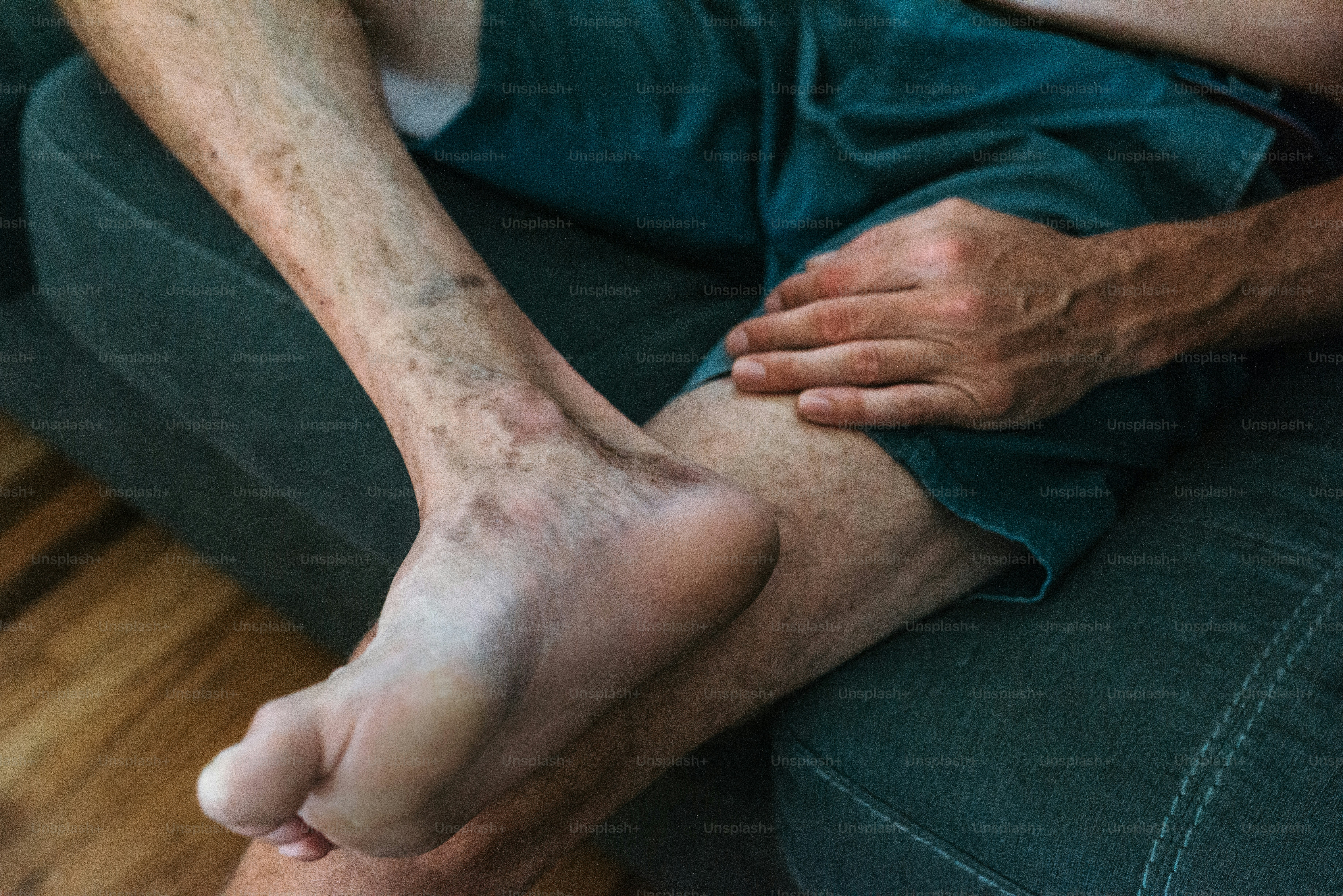 A man sitting on a couch holding his leg photo – Leg Image on Unsplash