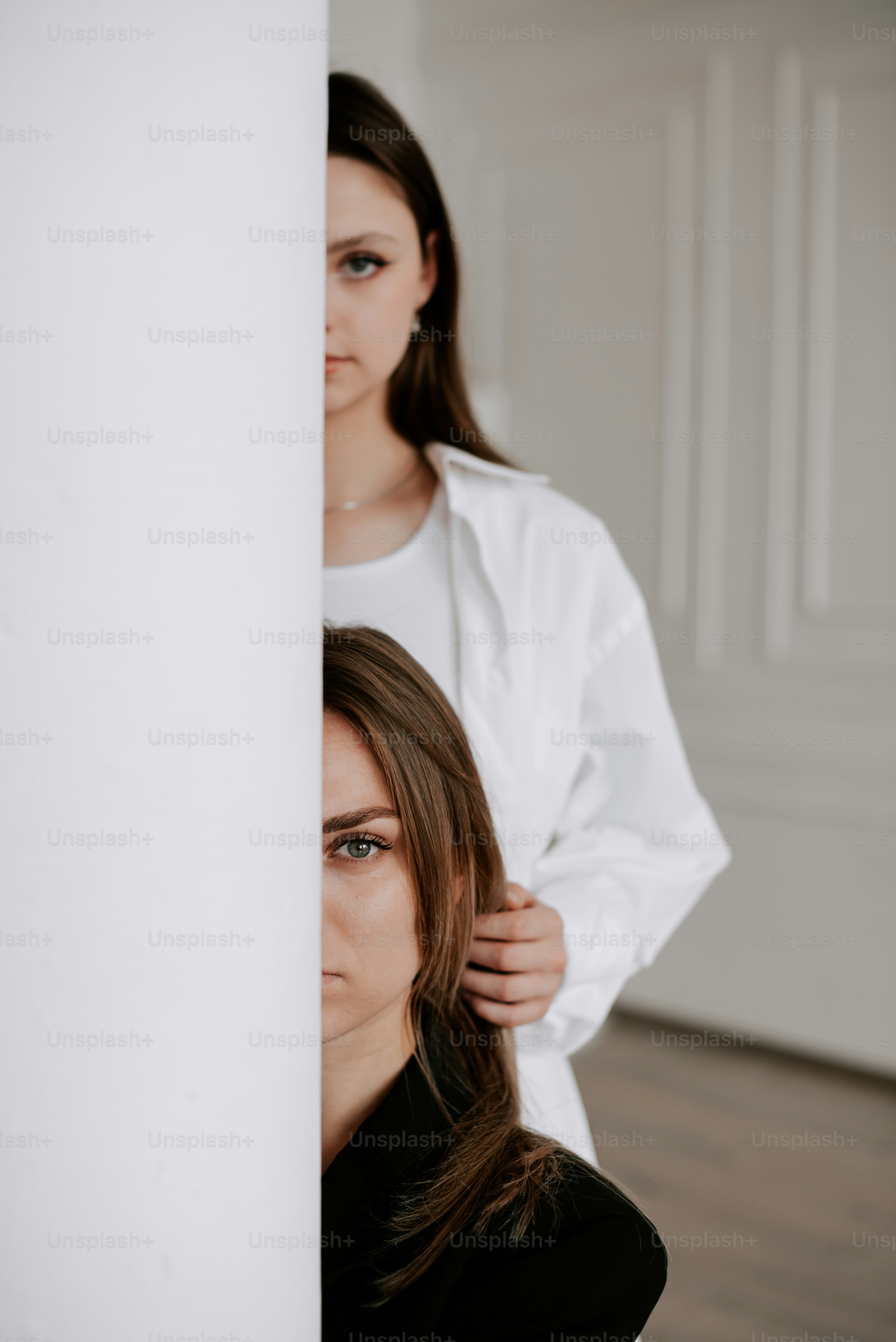 A woman standing behind a column with her hands on her shoulder photo ...