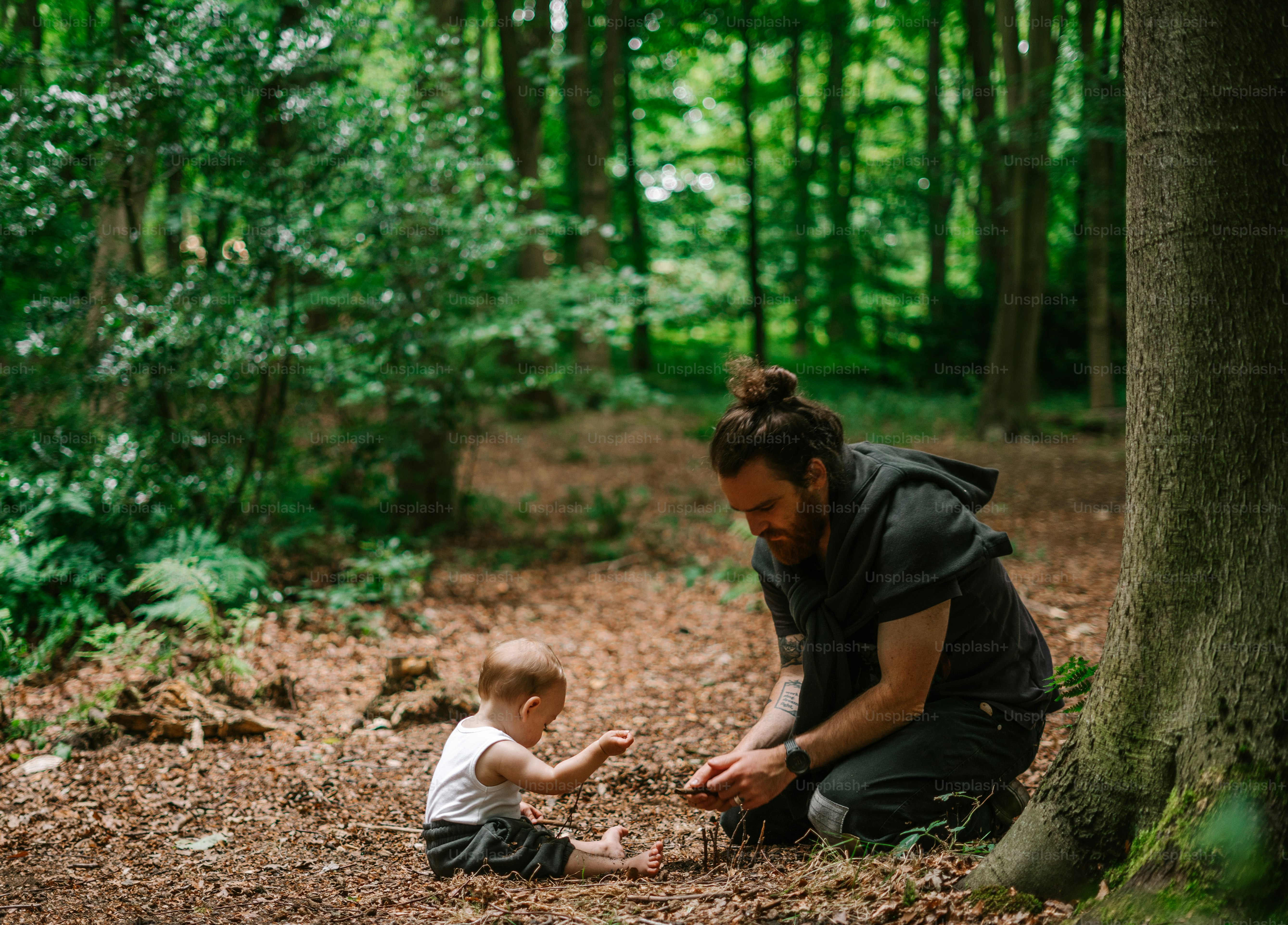 A man holding a child in his arms in the woods photo – Father Image on ...