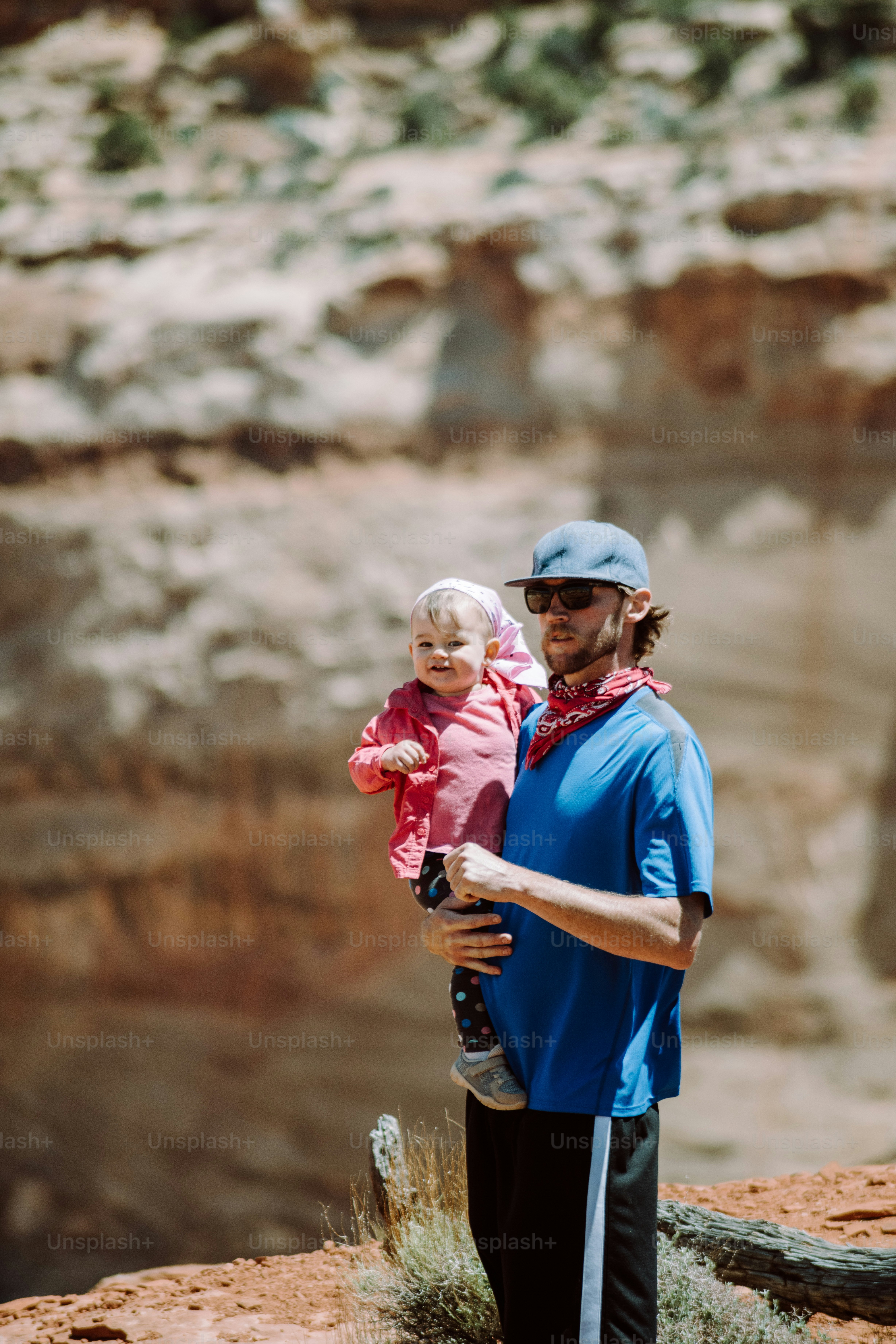 Foto Un hombre sosteniendo a un bebé parado en la cima de un acantilado ...