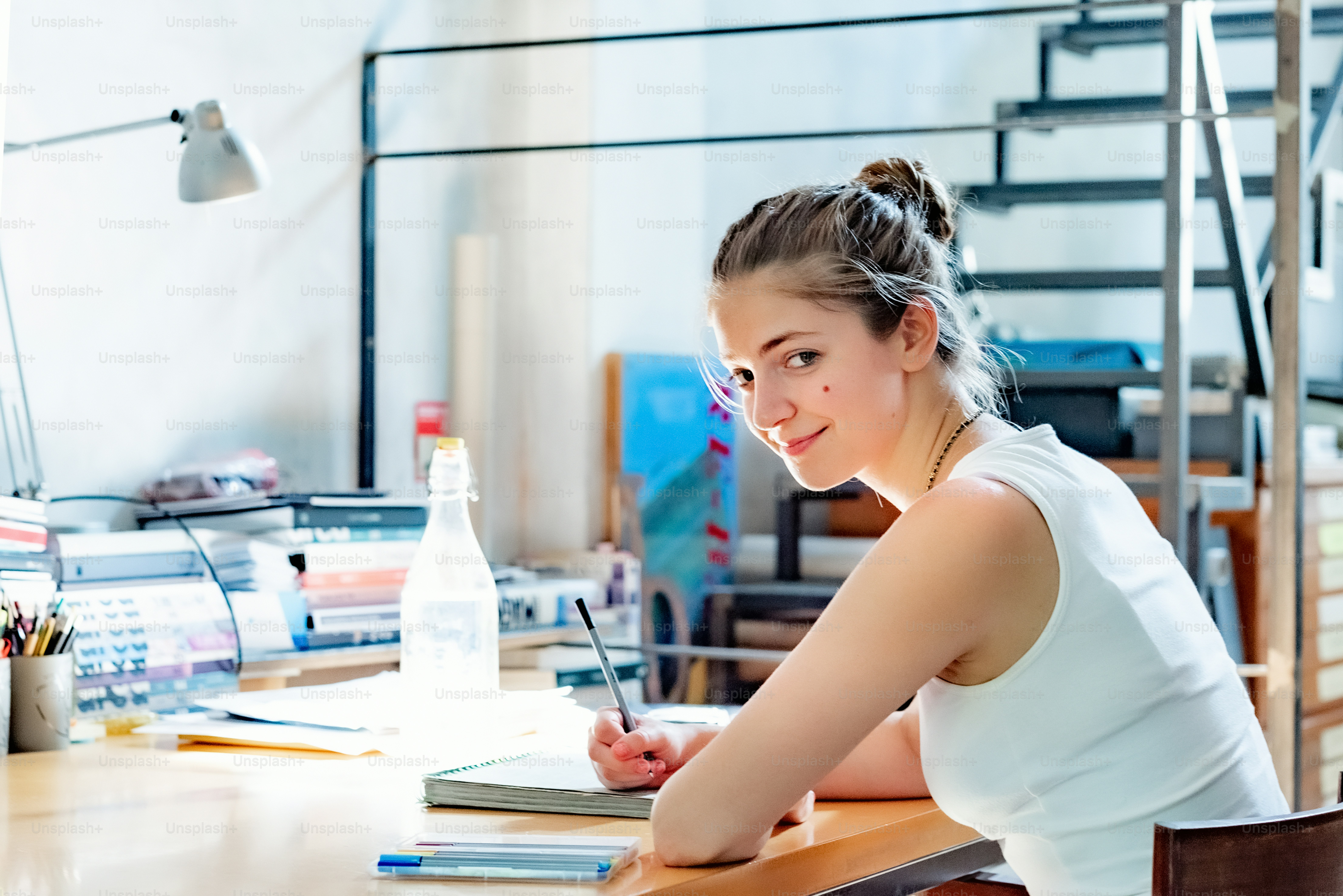 A woman sitting at a desk writing on a notebook photo – Photoshoot ...