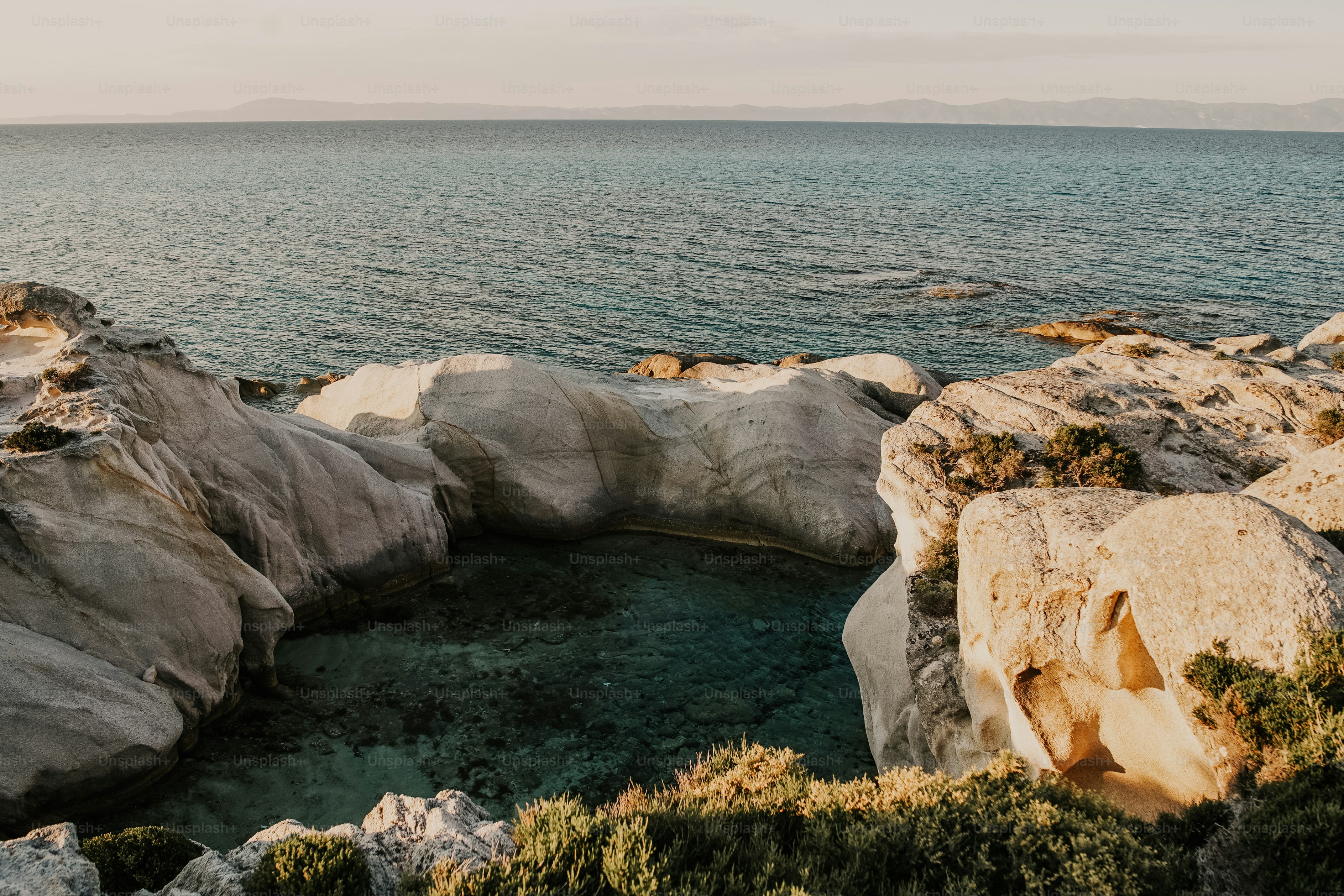 A large body of water surrounded by rocks photo – Coast Image on Unsplash