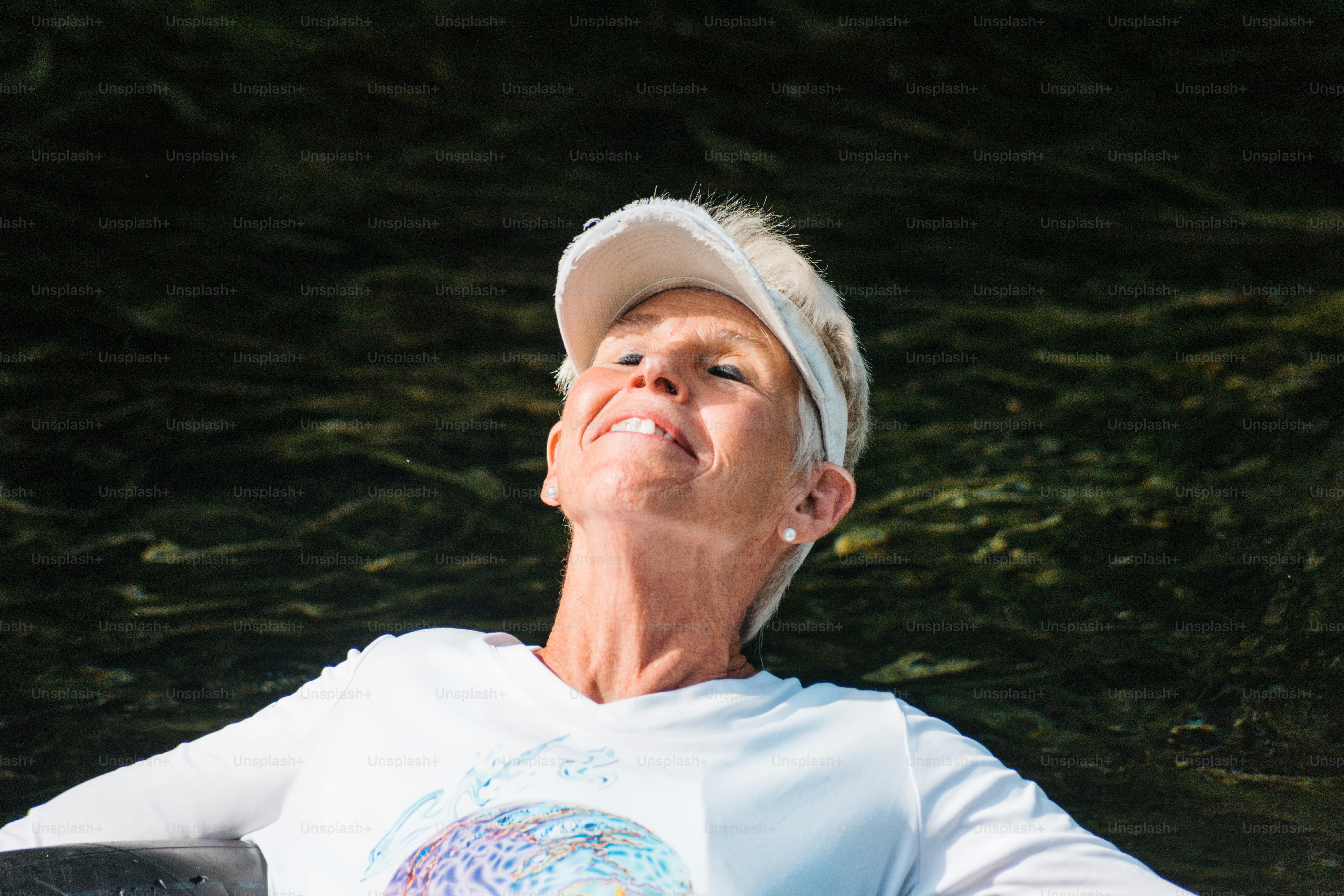 A woman floating on top of a body of water photo – Older people Image ...