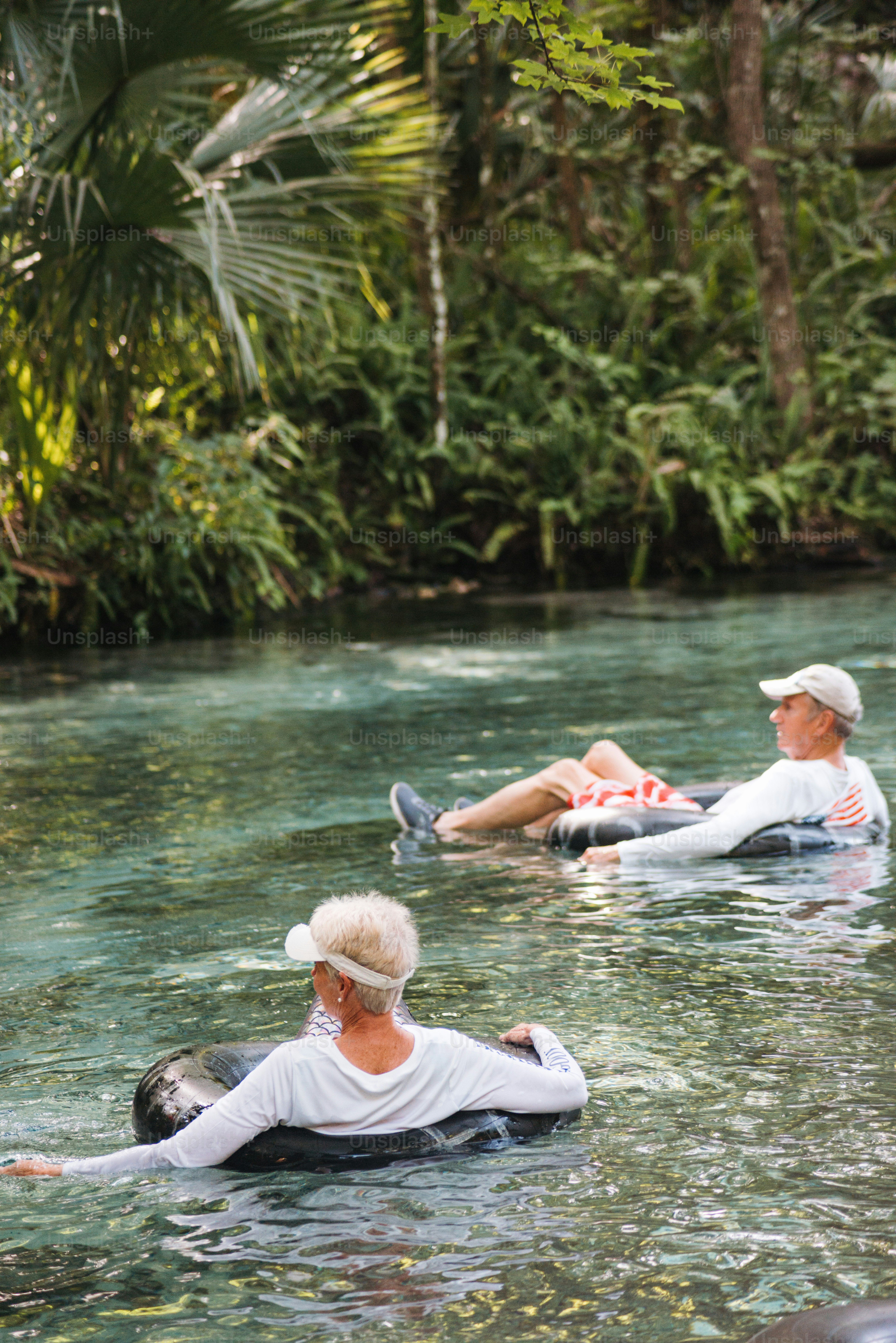 A couple of people floating on top of a body of water photo – Senior ...