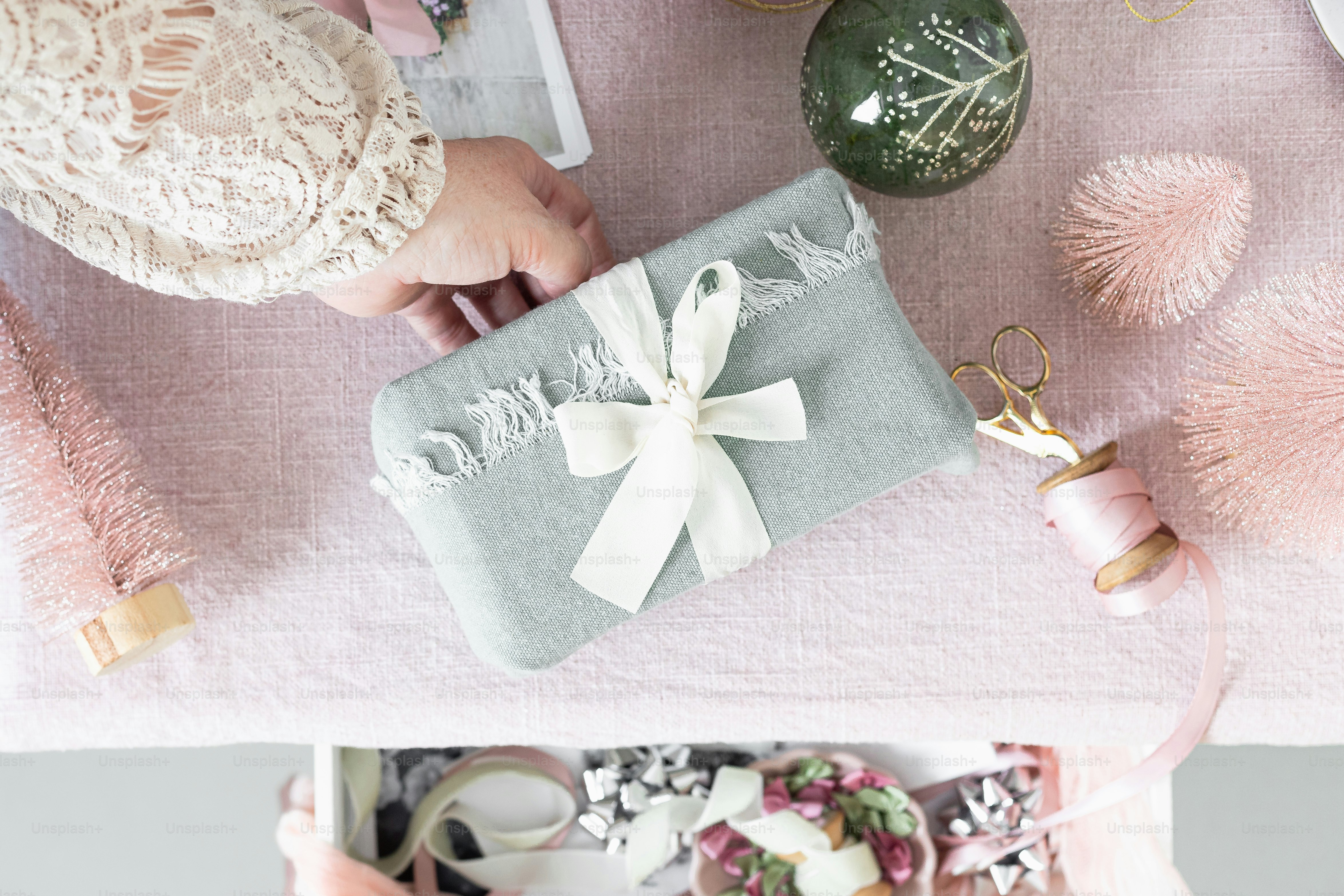 A woman holding a wrapped present on top of a table photo – Baubles ...